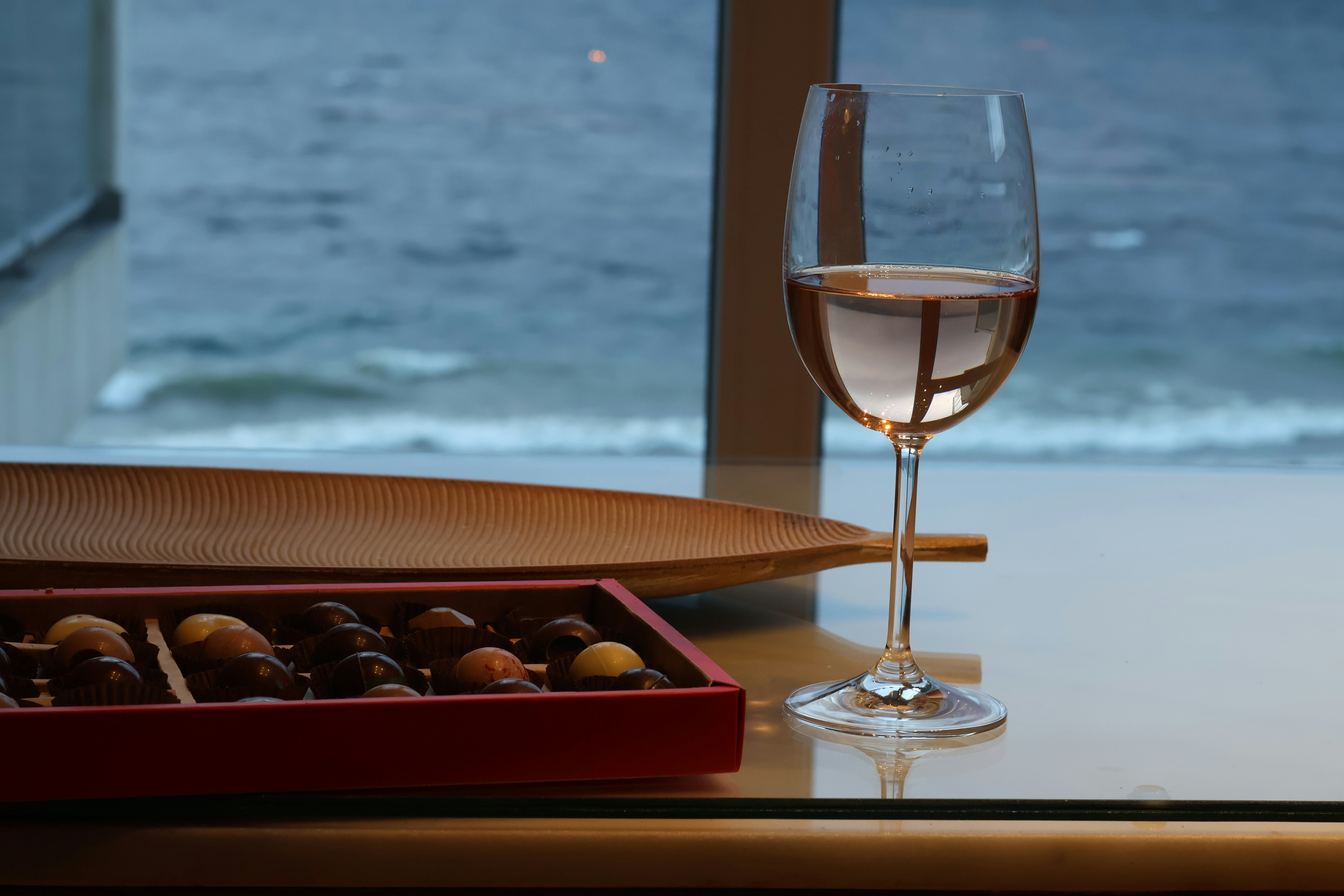 Glass of wine and chocolates by the window