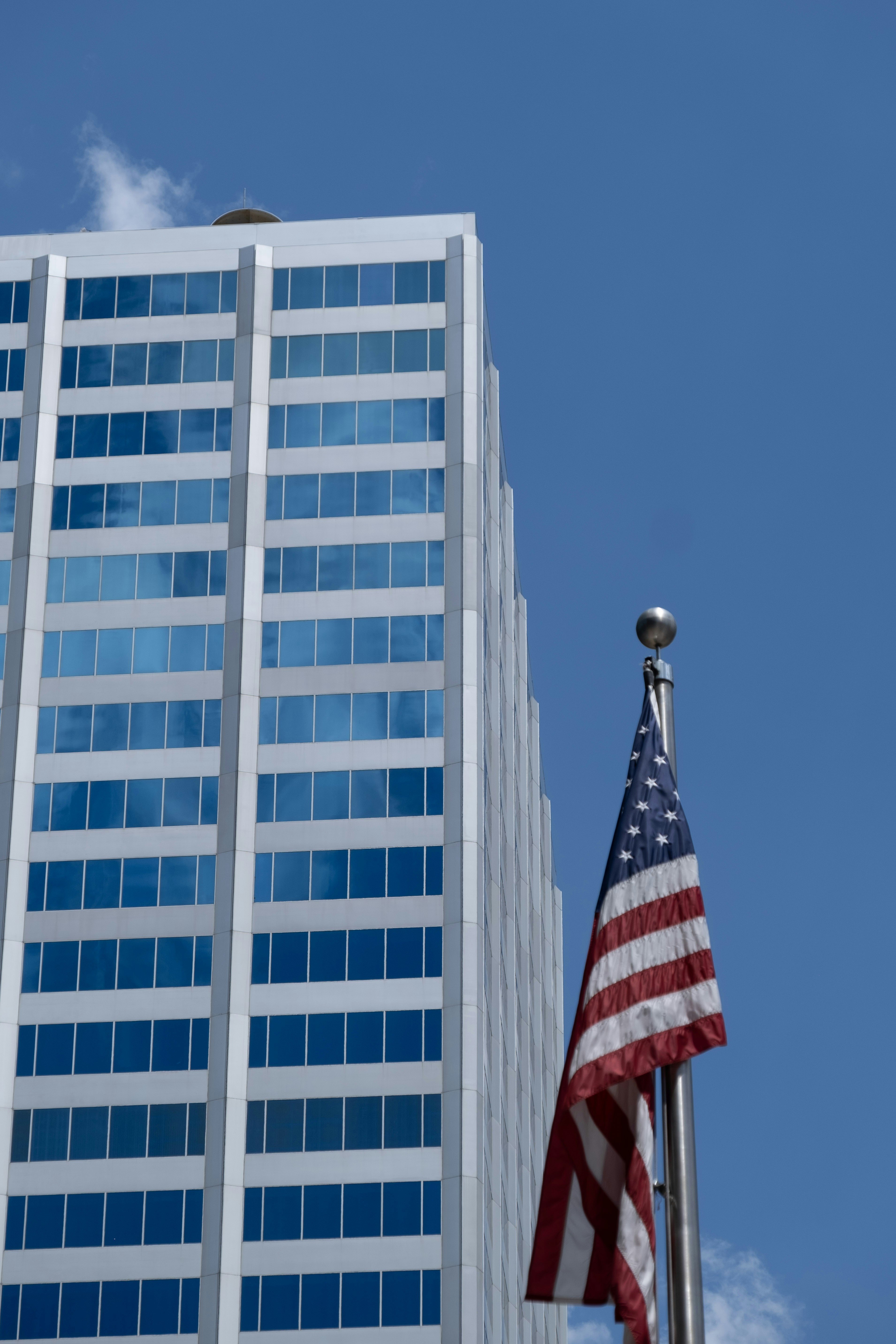Bank Skyscraper building downtown | American flag waves near a modern glass skyscraper
