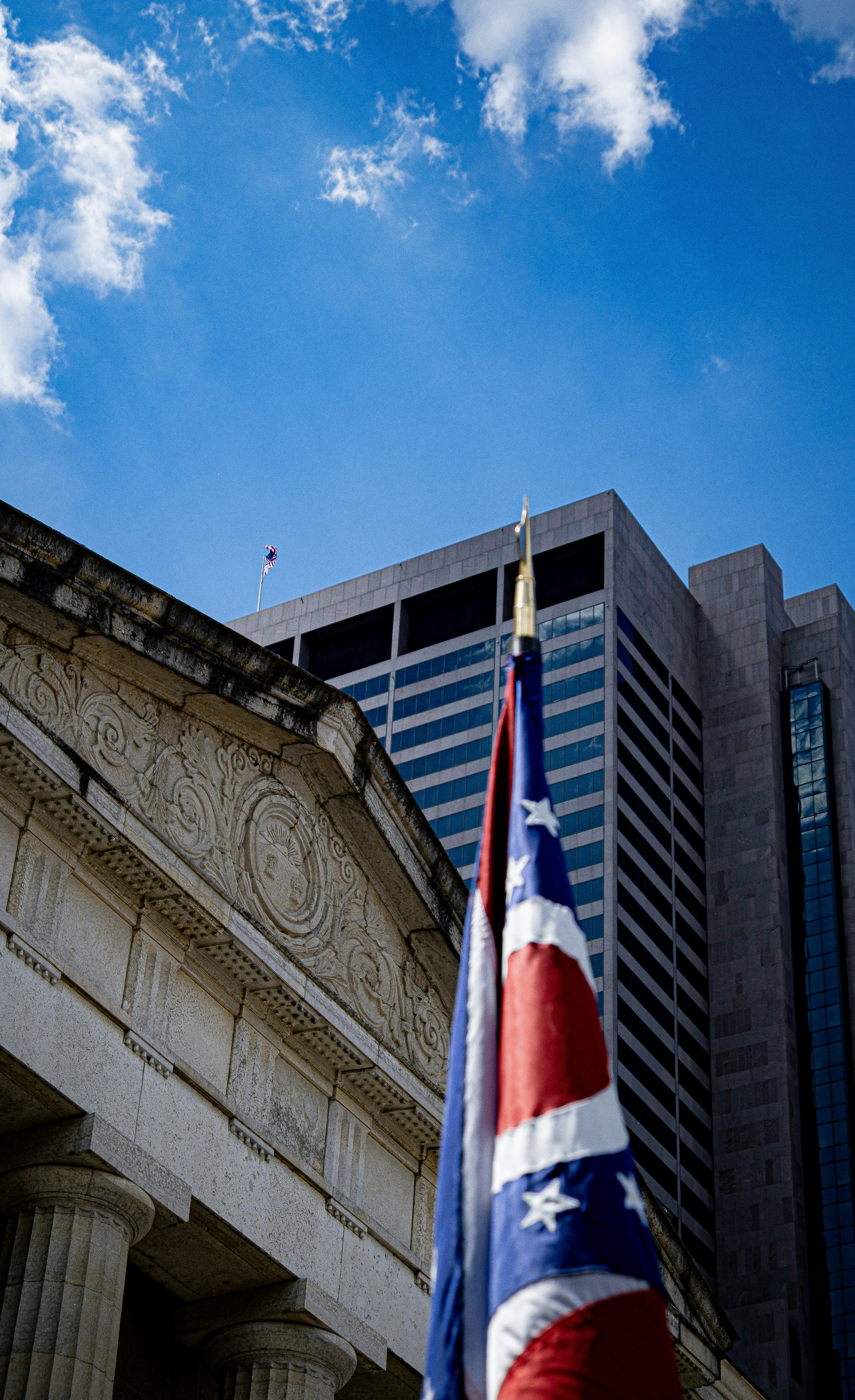 Flags wave in front of buildings under blue sky