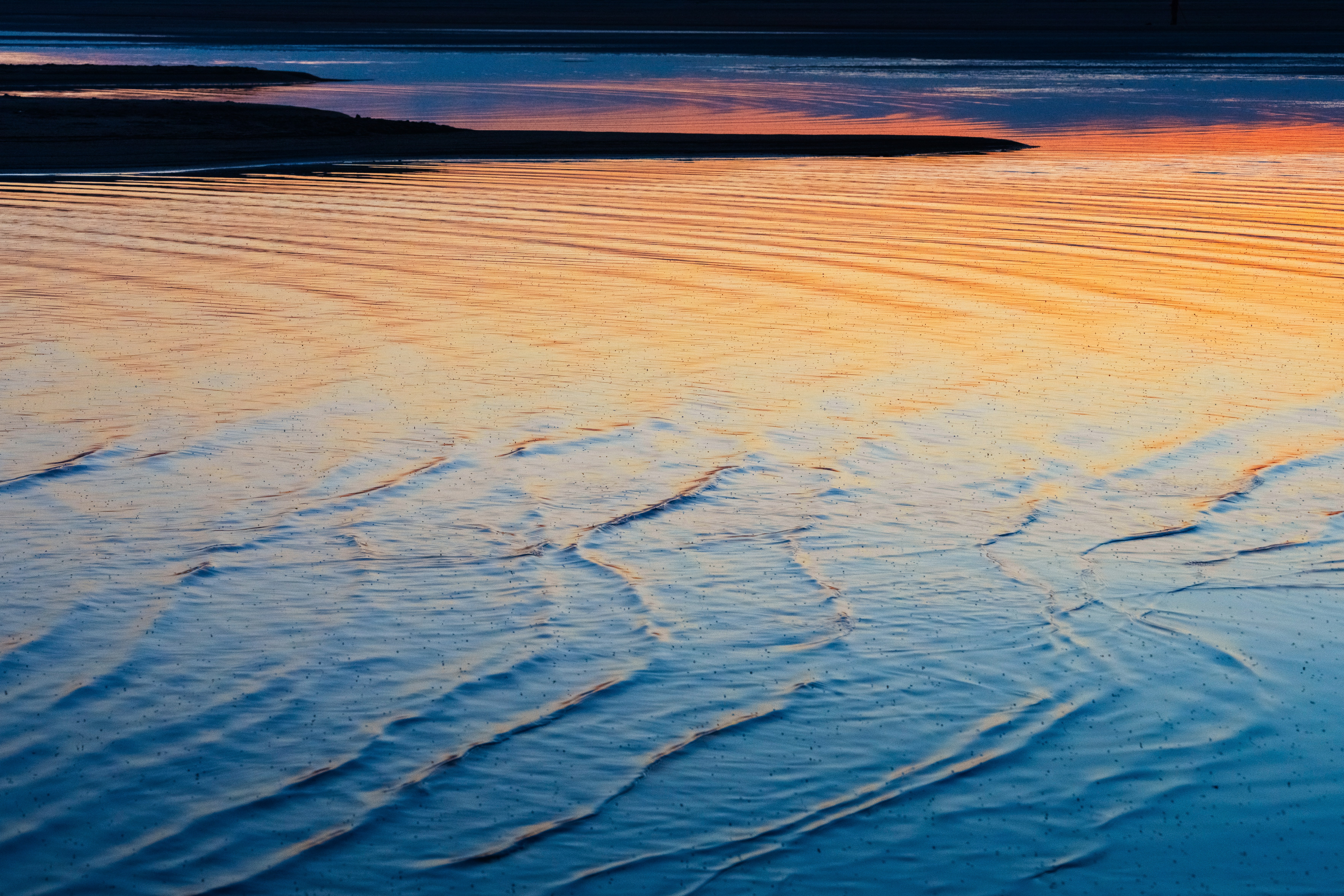 Gentle ripples in a serene body of water reflect the soft hues of twilight, creating a tranquil atmosphere.