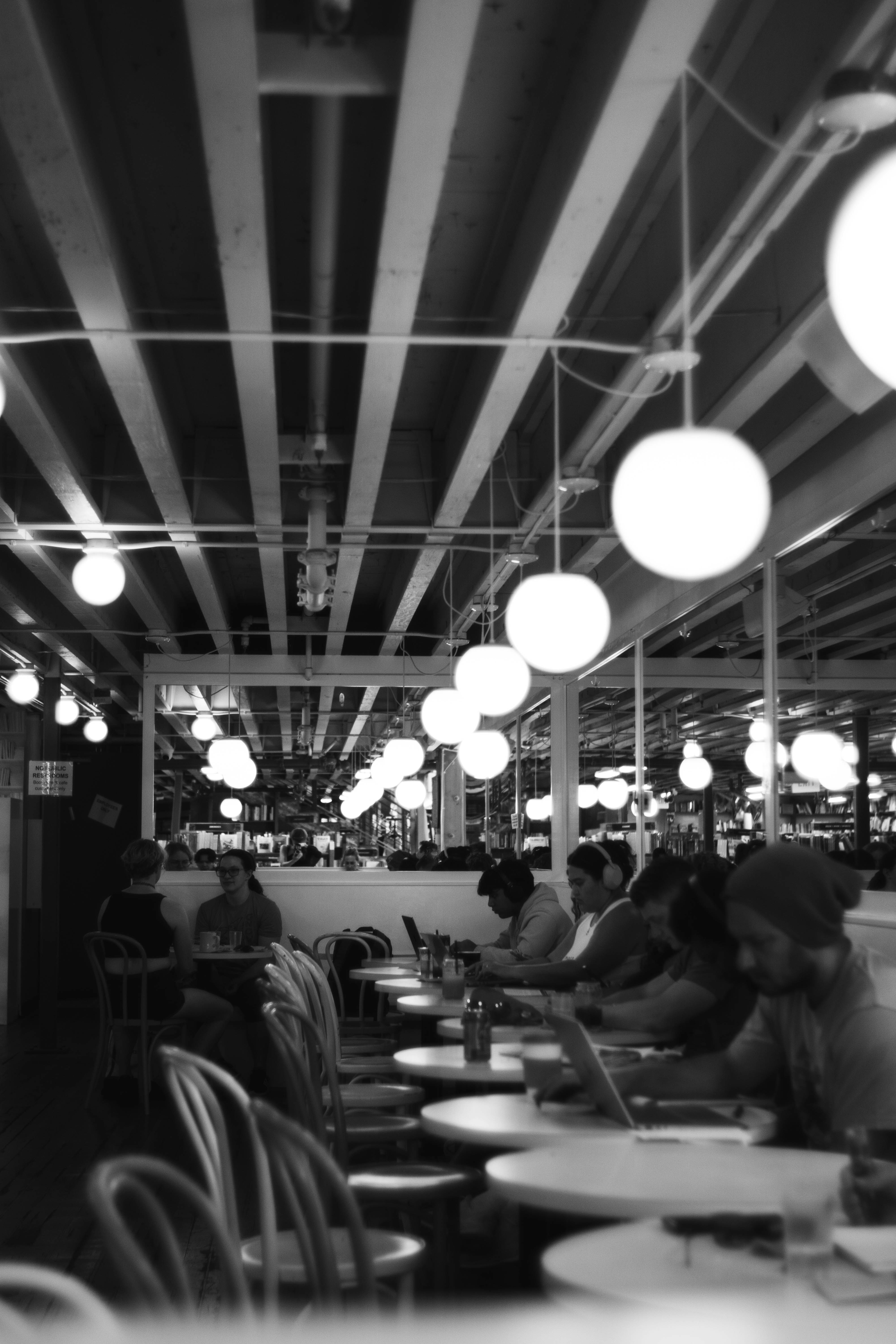 Cozy café interior featuring patrons engaged in conversation and work under soft, glowing pendant lights.