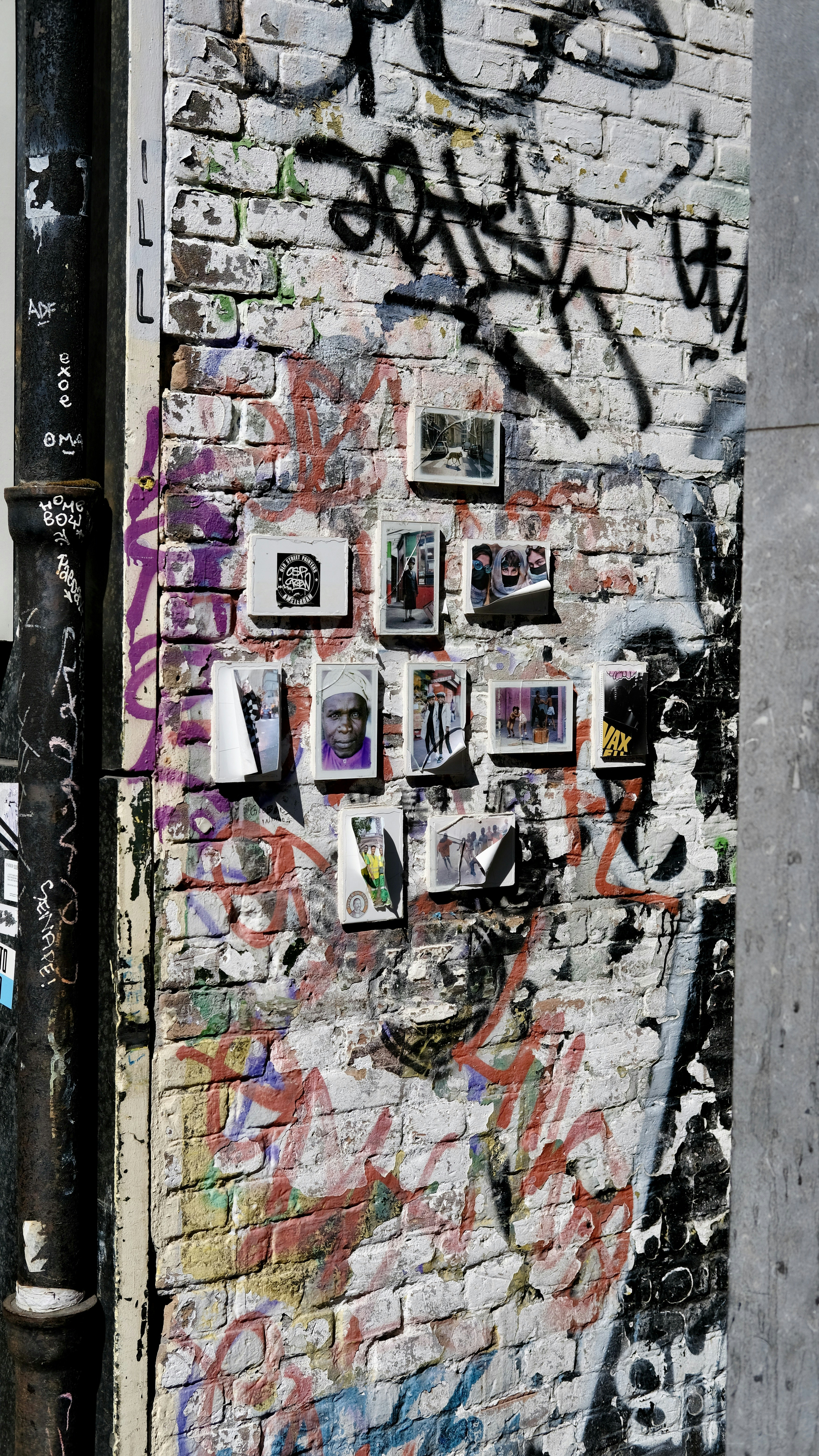 close-up of a graffiti-covered brick wall in an urban alley, featuring a creative collage of photographs pasted onto the surface. The vibrant mix of spray-painted tags, textures, and weathered posters captures the raw energy and artistic expression of the city street scene. | Graffiti-covered brick wall with framed pictures attached photos attached pictures.