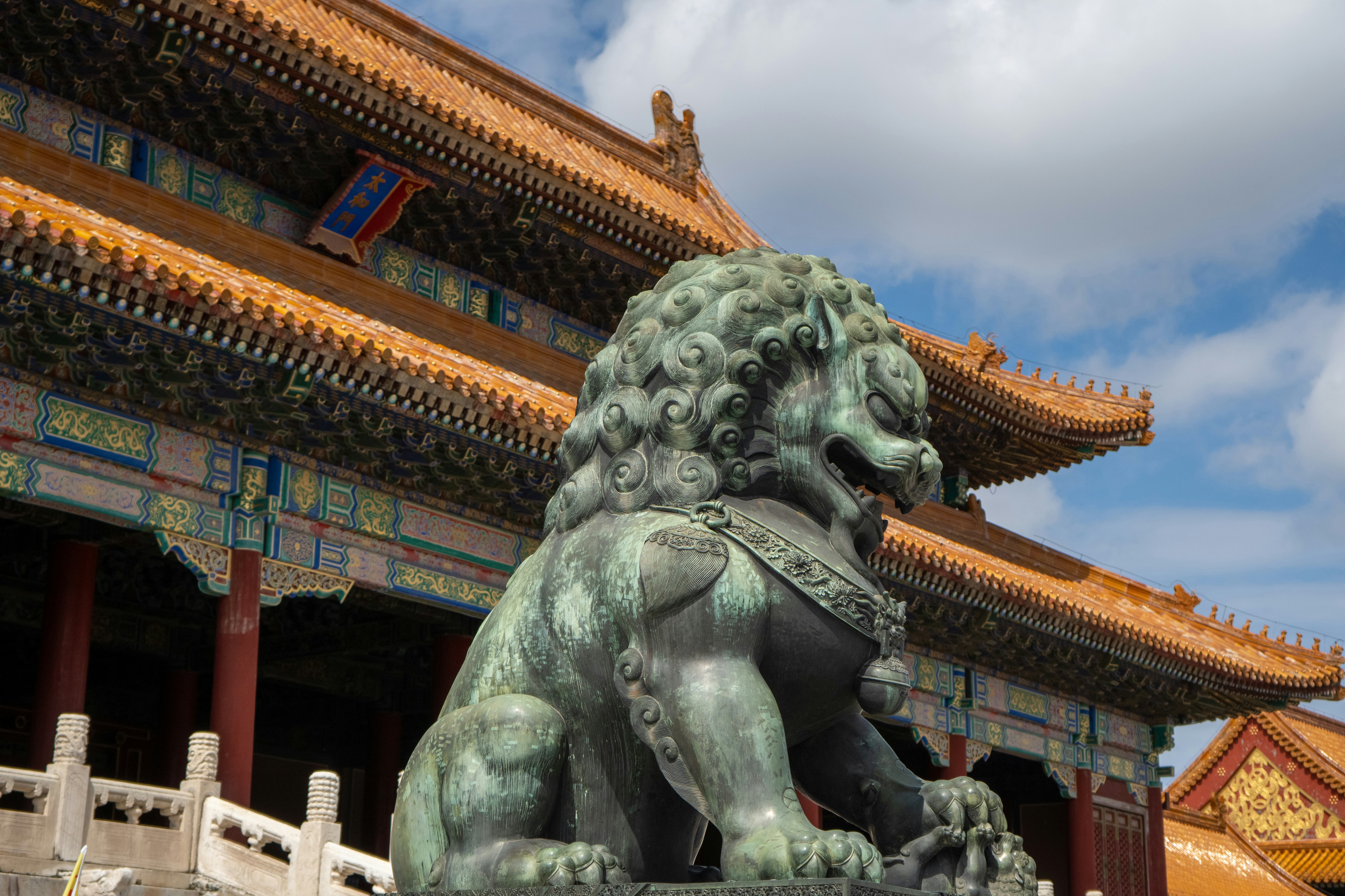Stone lion statue in front of traditional chinese building