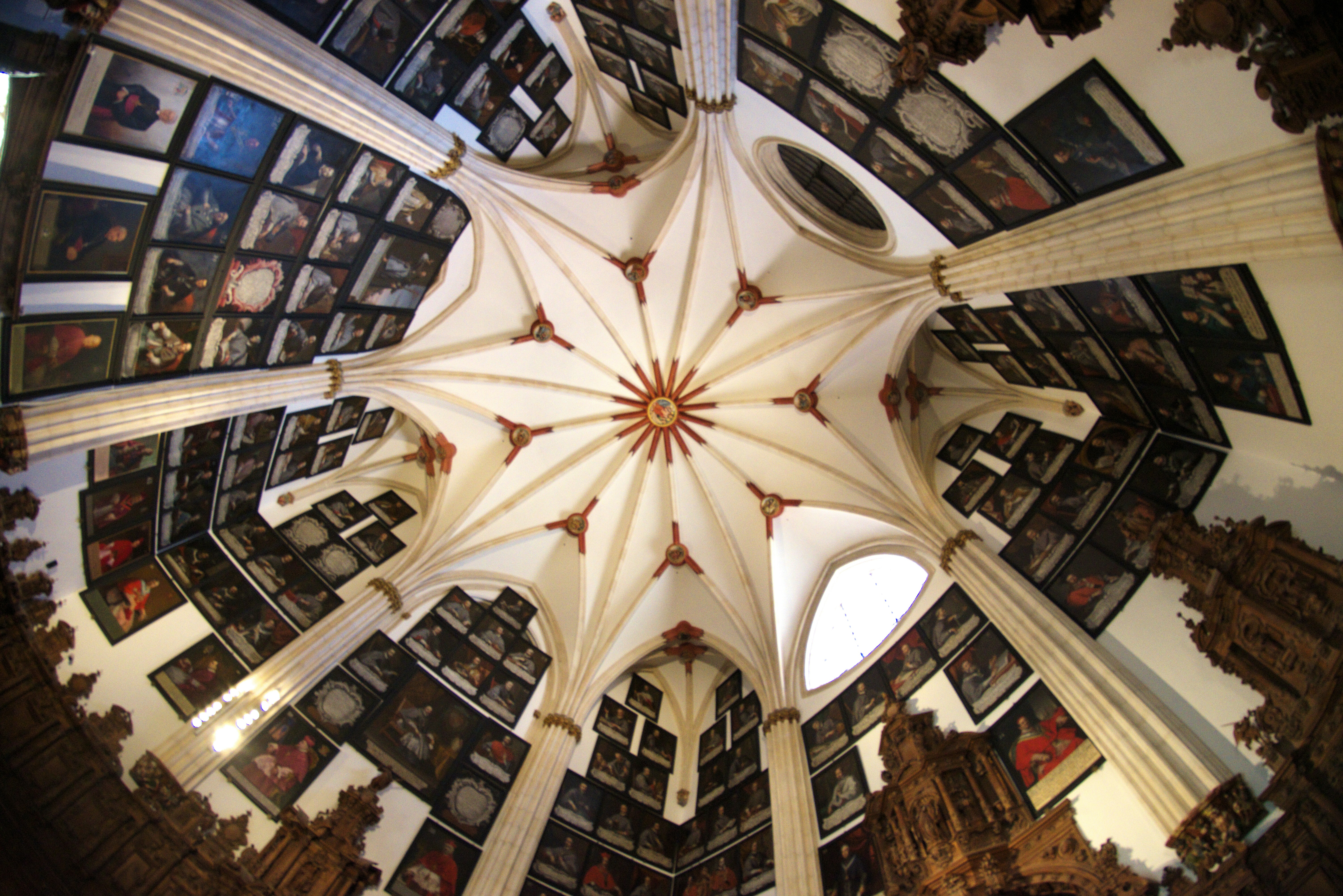 Intricate ceiling design adorned with historical portraits in a grand hall, showcasing artistic craftsmanship and architectural beauty.