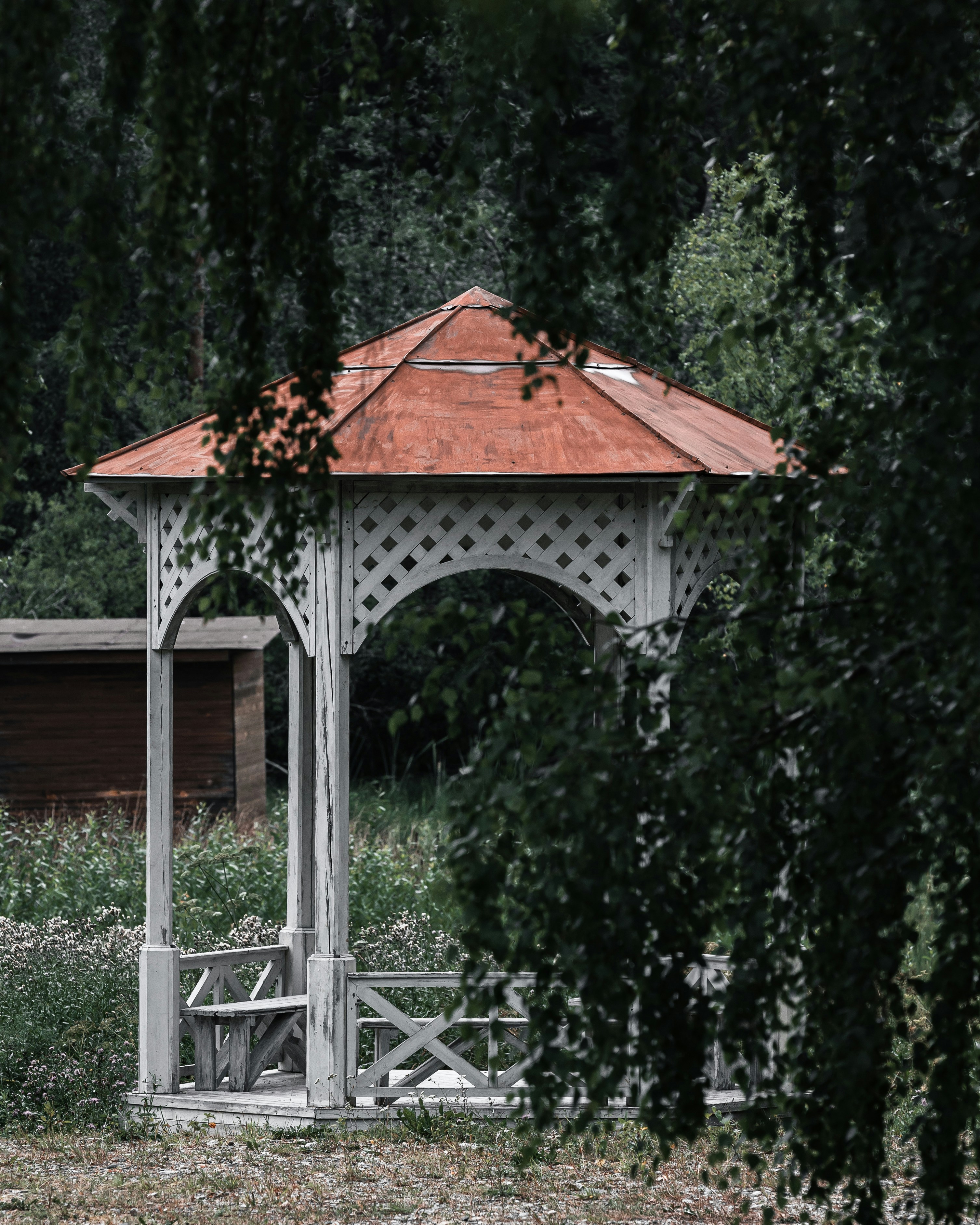 White gazebo with red roof surrounded by trees
