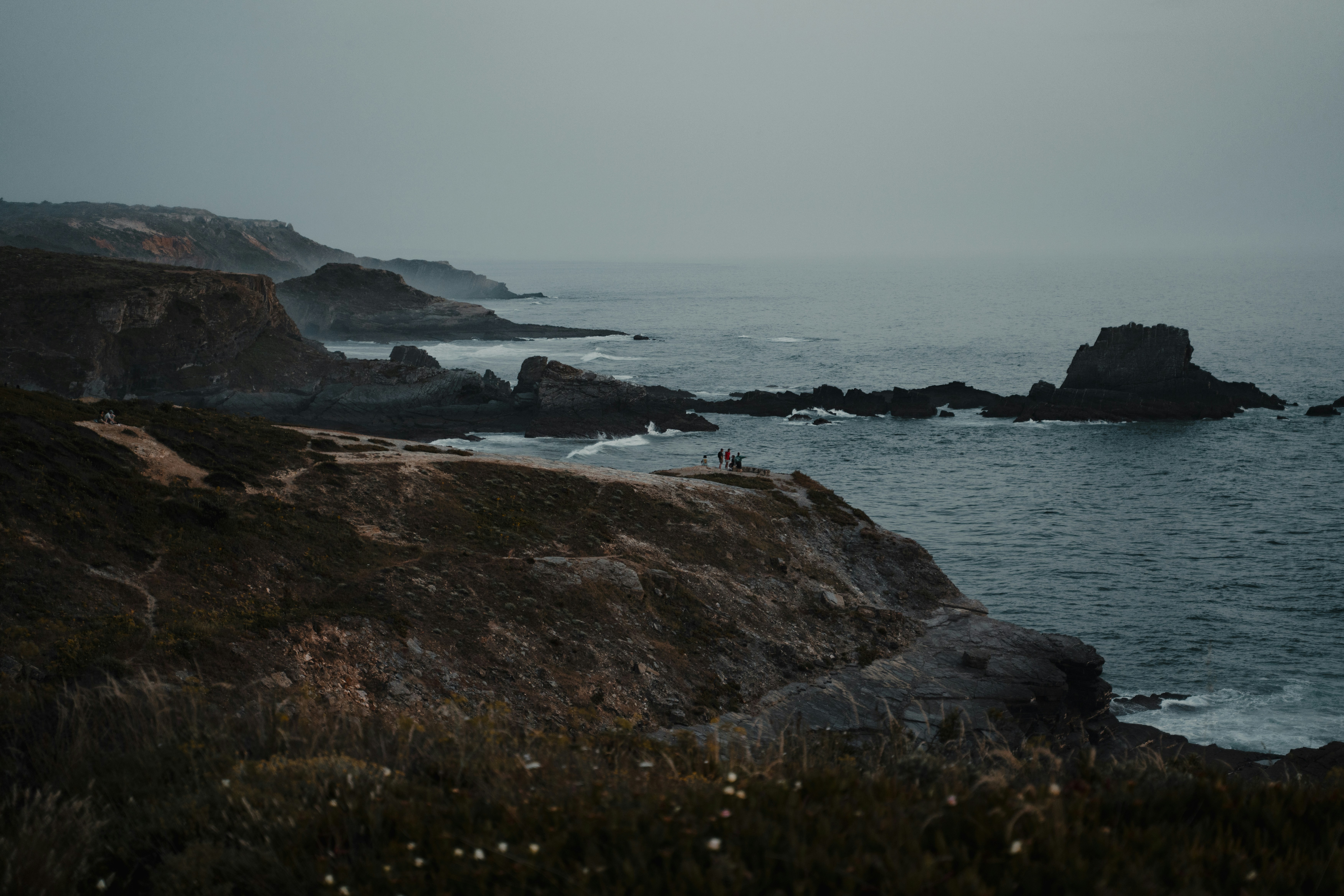 Rocky coastline with calm sea under overcast sky