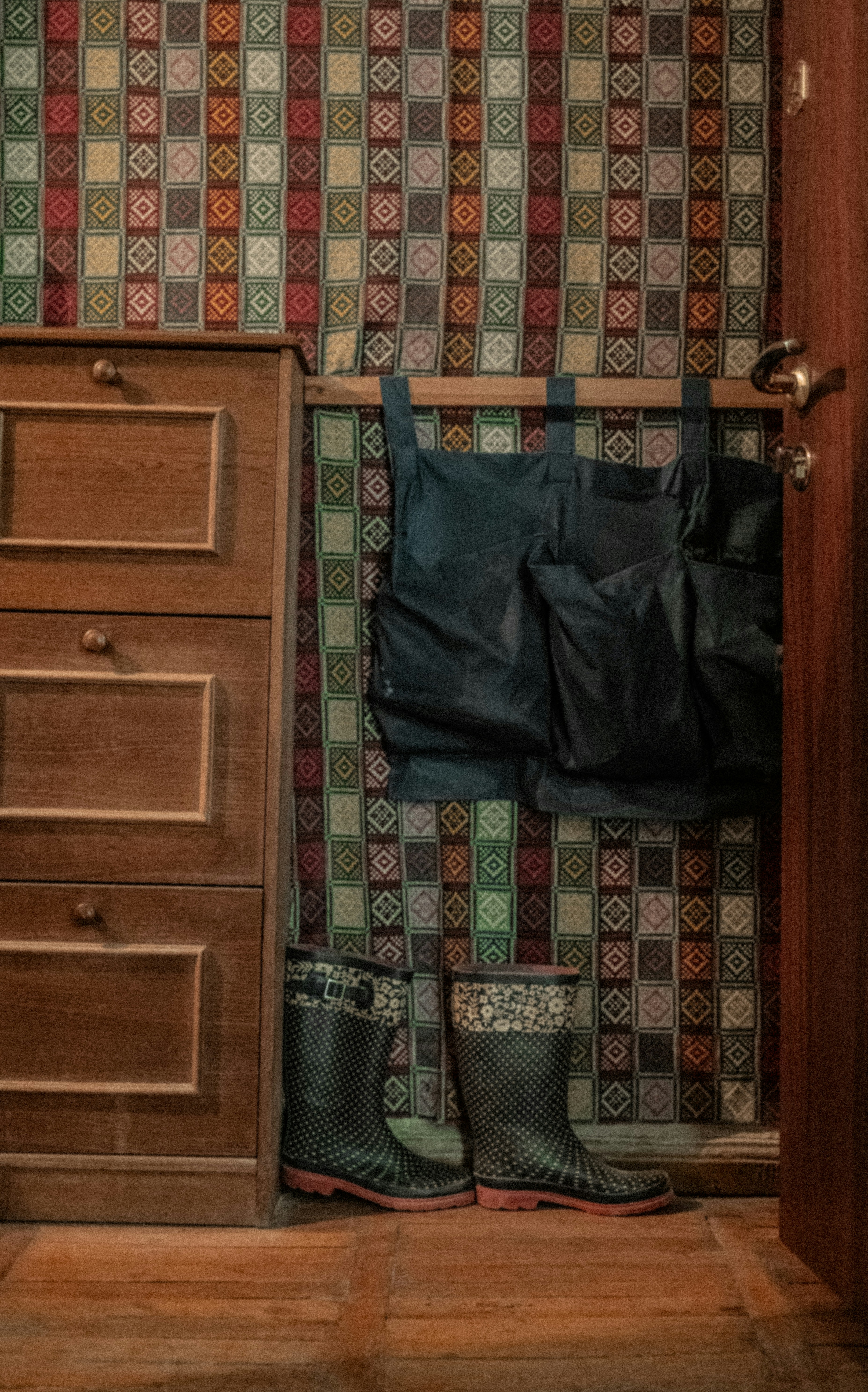 Rubber boots after the rain | Pair of boots in front of patterned wallpaper and wooden cabinet.