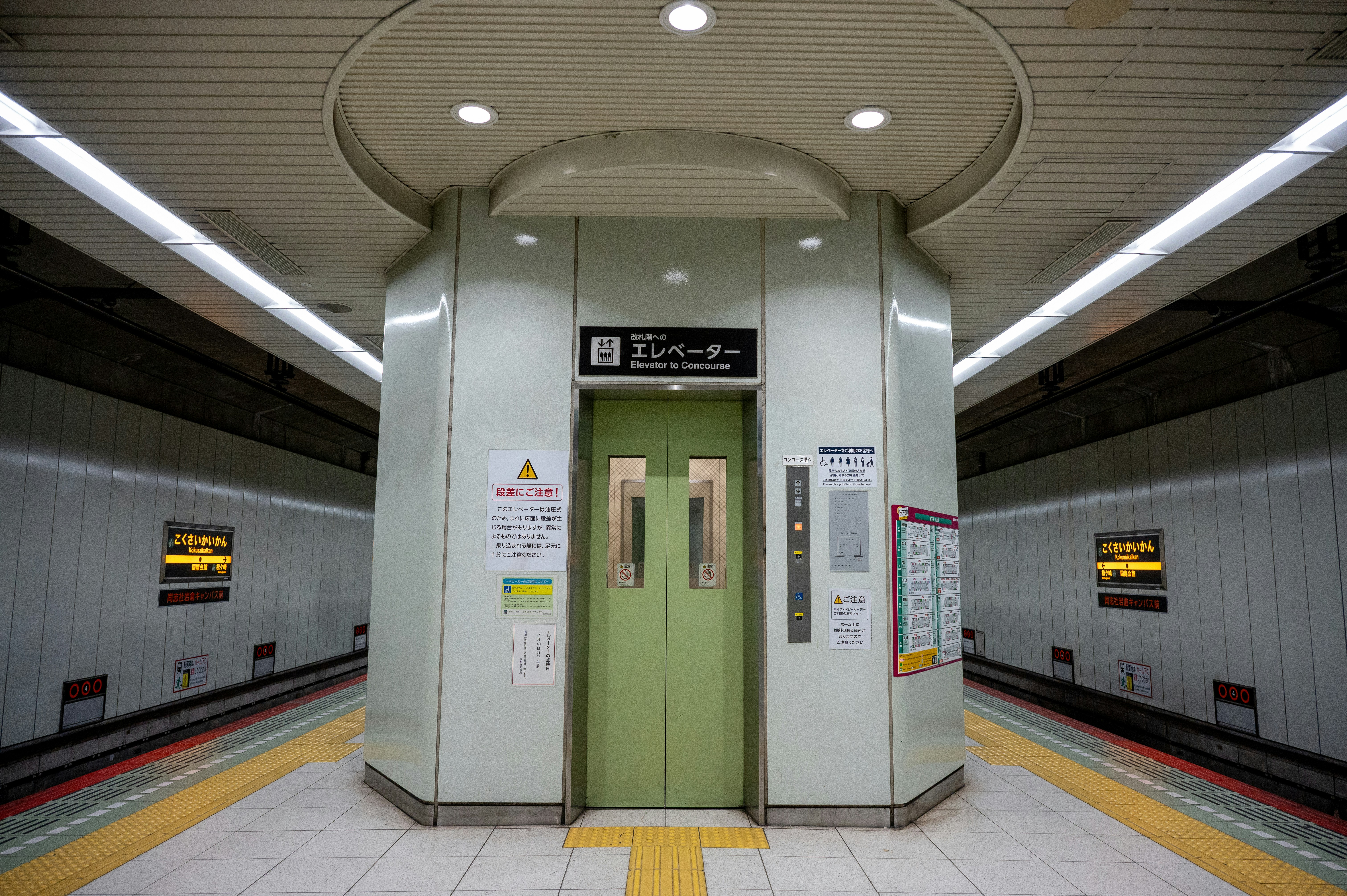 Green elevator doors in a modern subway station.