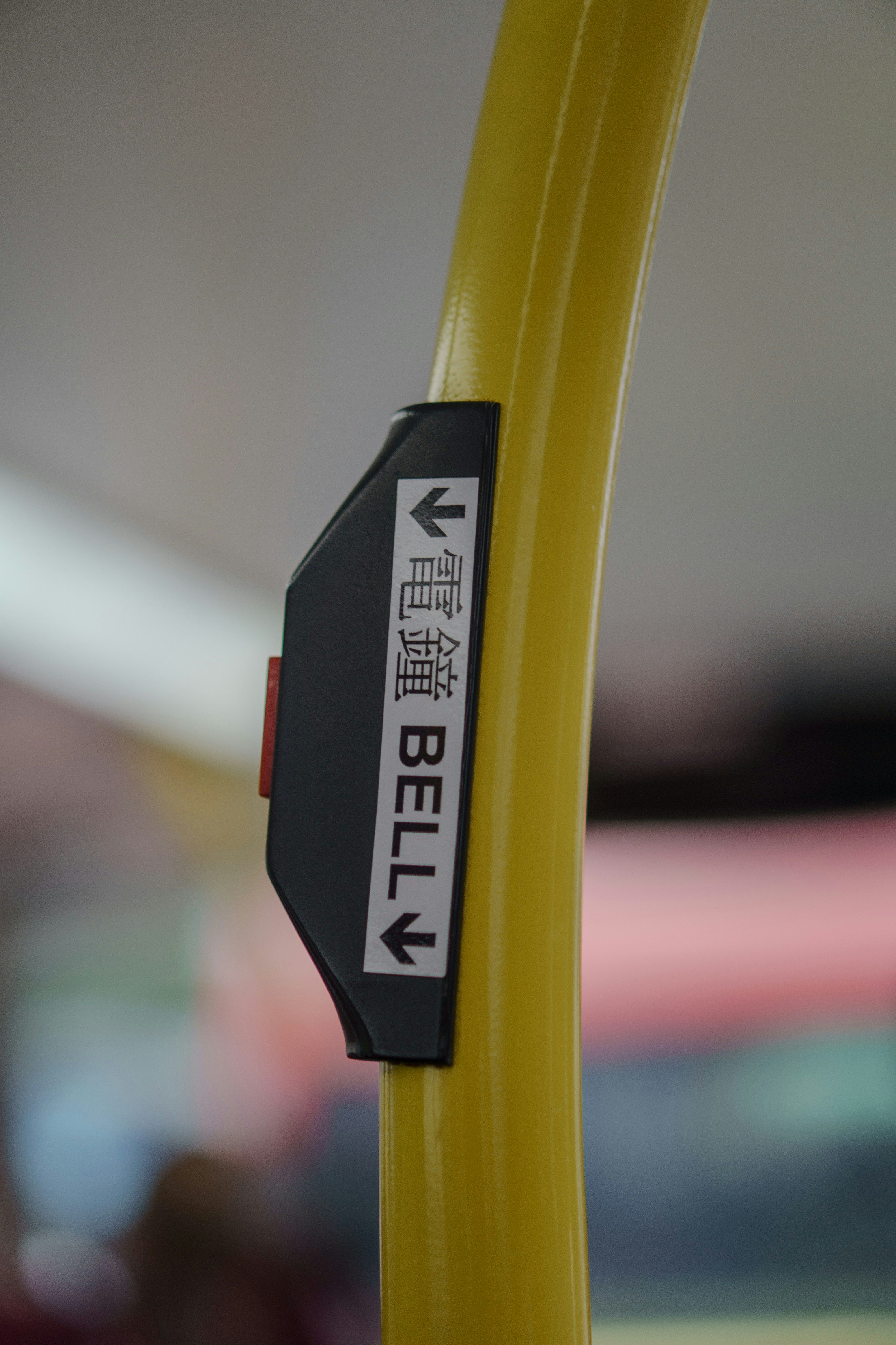 Bell Tag on a Yellow Transit Pole: A Sharp Moment of Public-Transit Detail
