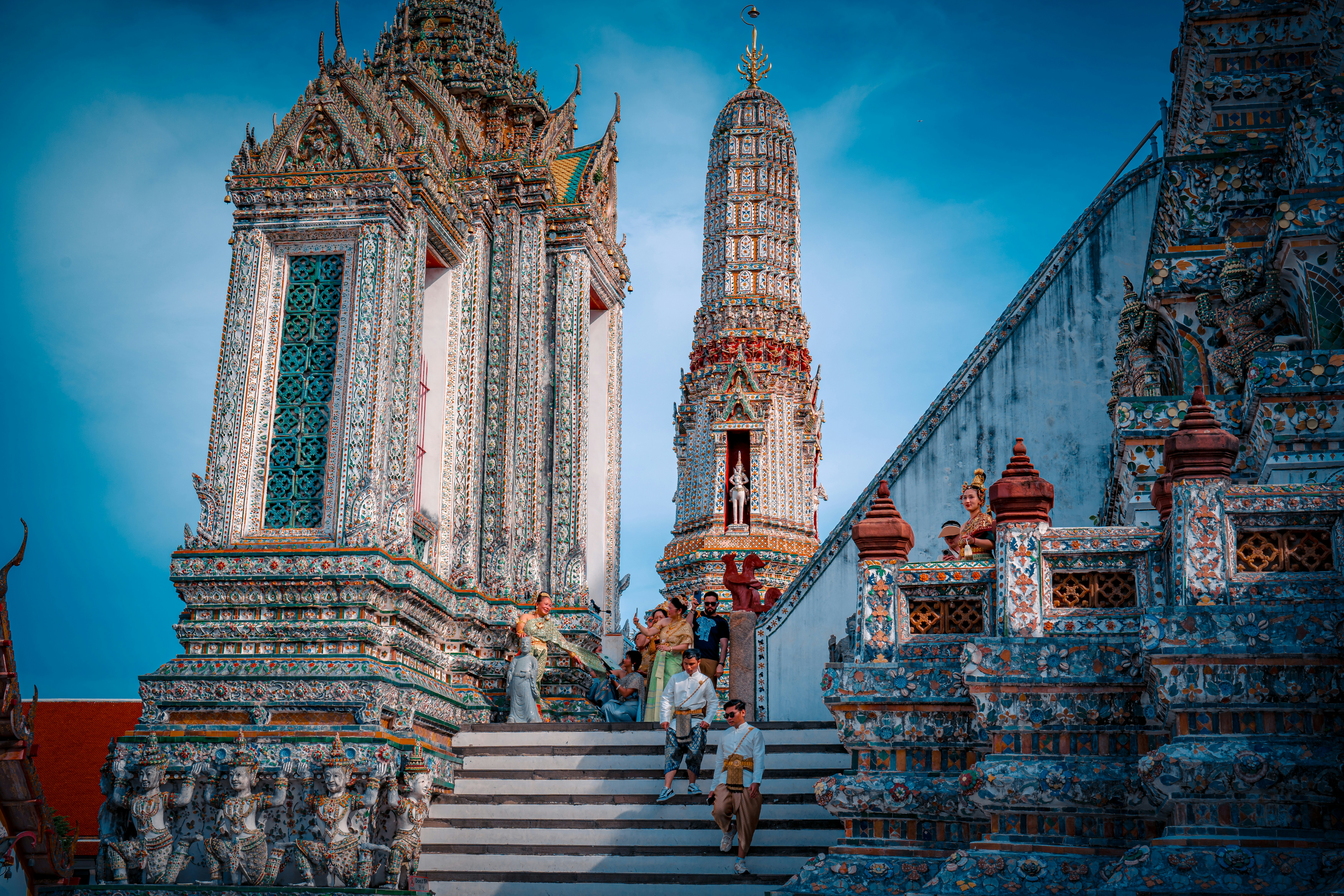 Intricate temple structures adorned with colorful mosaics, overlooking visitors as they ascend the steps toward the towering spire.