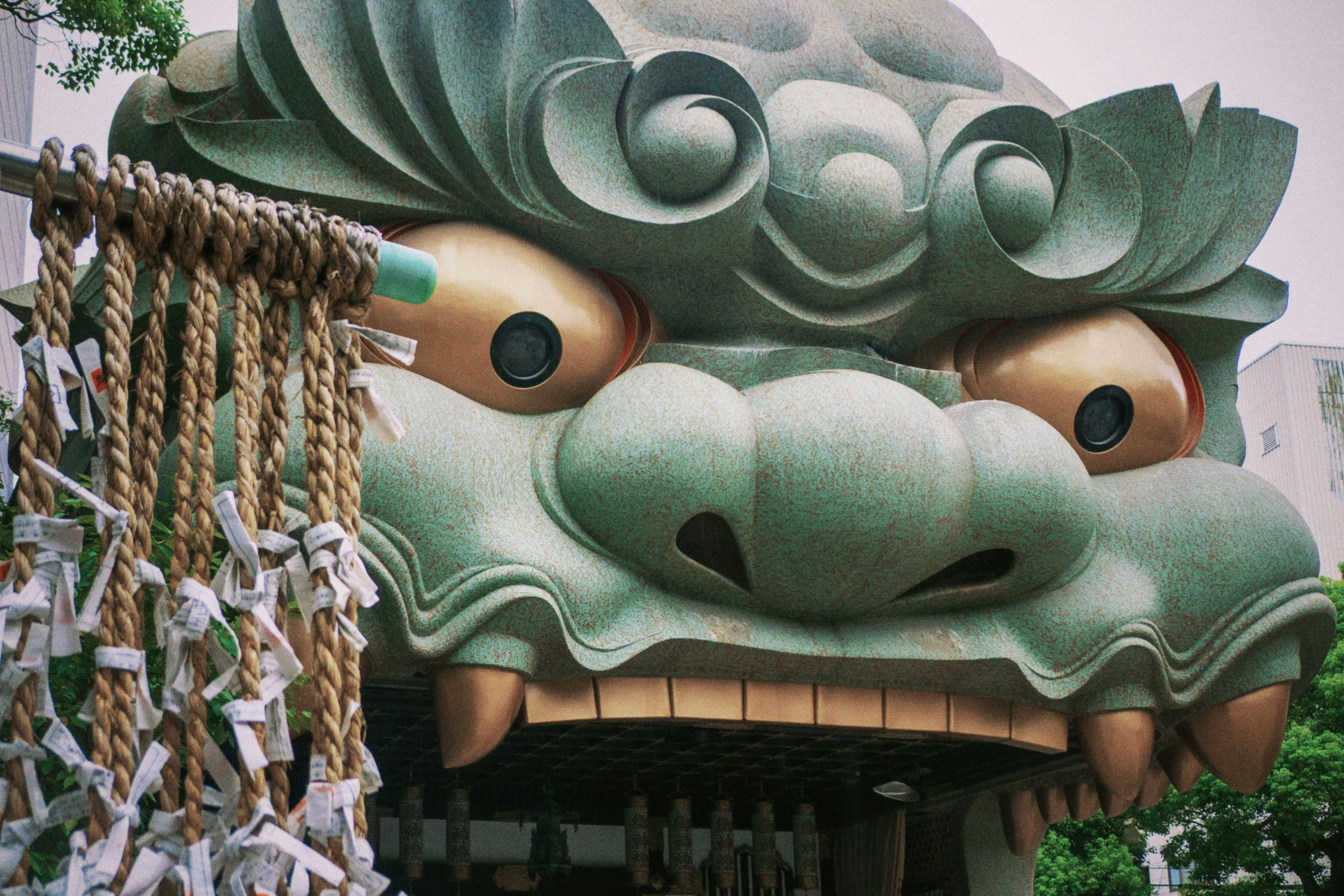 Large green mythical creature head with gold eyes