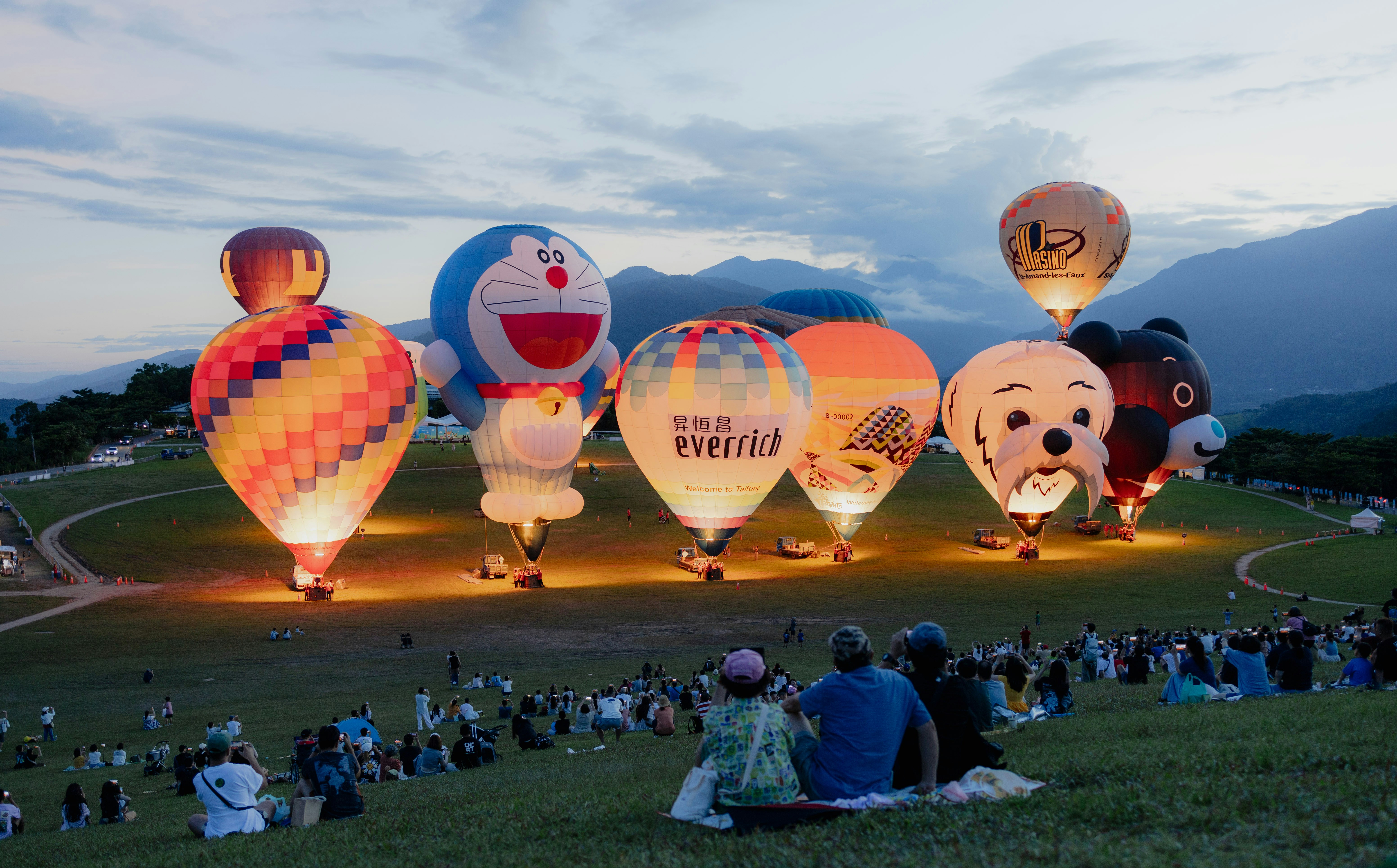 Hot air balloons shaped like cartoon characters at dusk