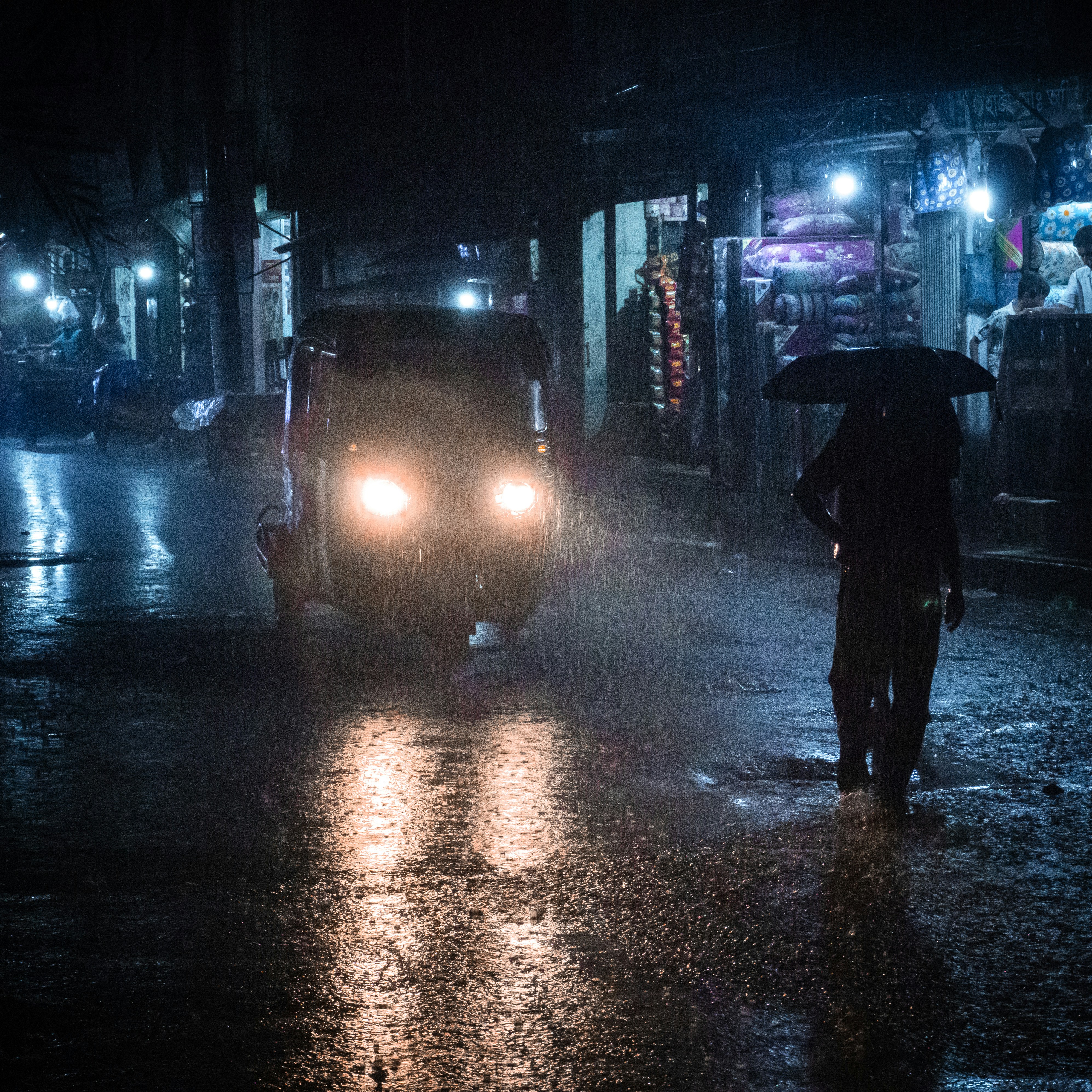 Person with umbrella walks on wet street at night