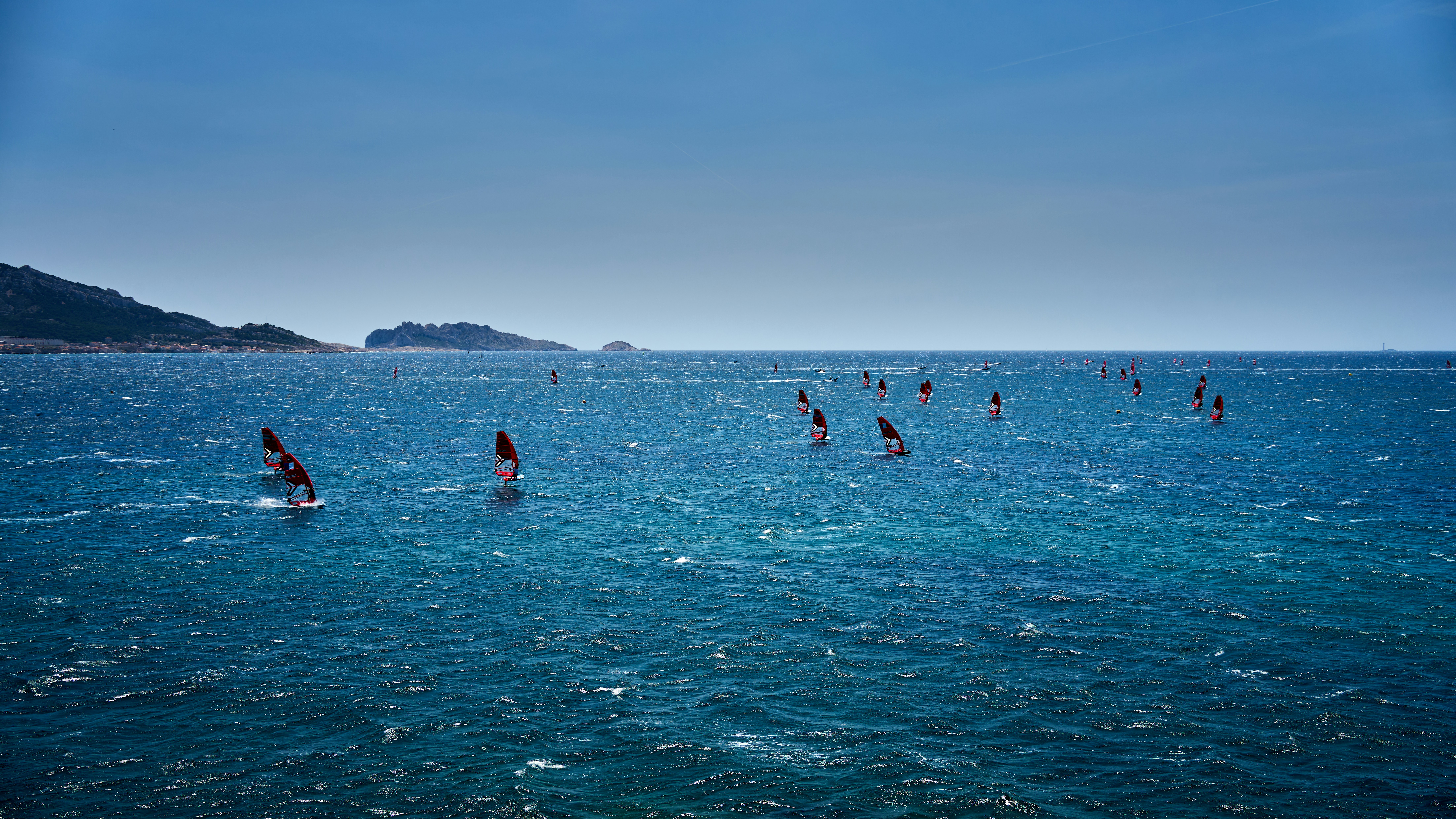 Wind-Swept Sea: A Ridge of Windsurfers across the Horizon