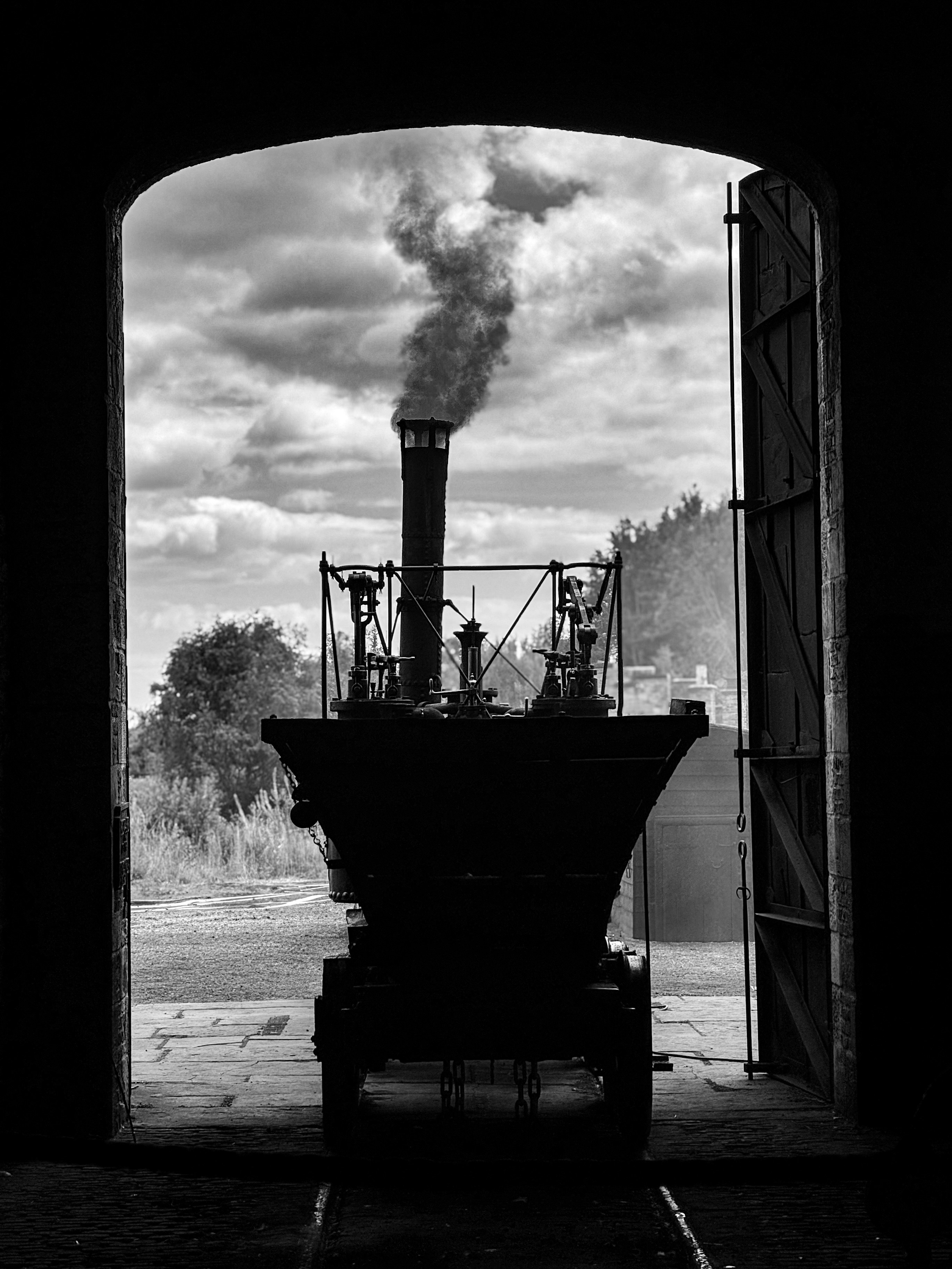 Steam train emerging from dark tunnel into daylight