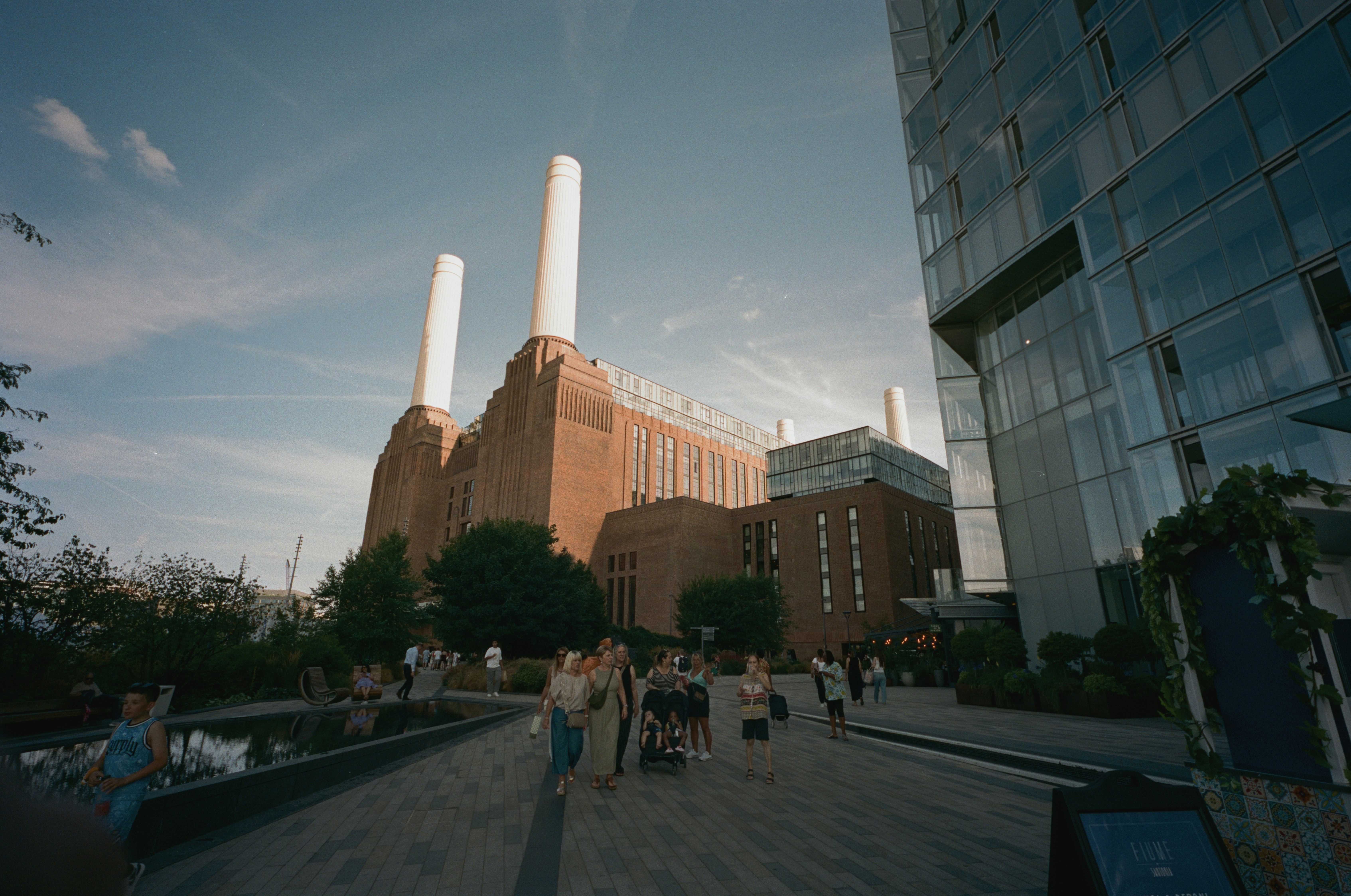 People walking near a large industrial building and modern architecture.