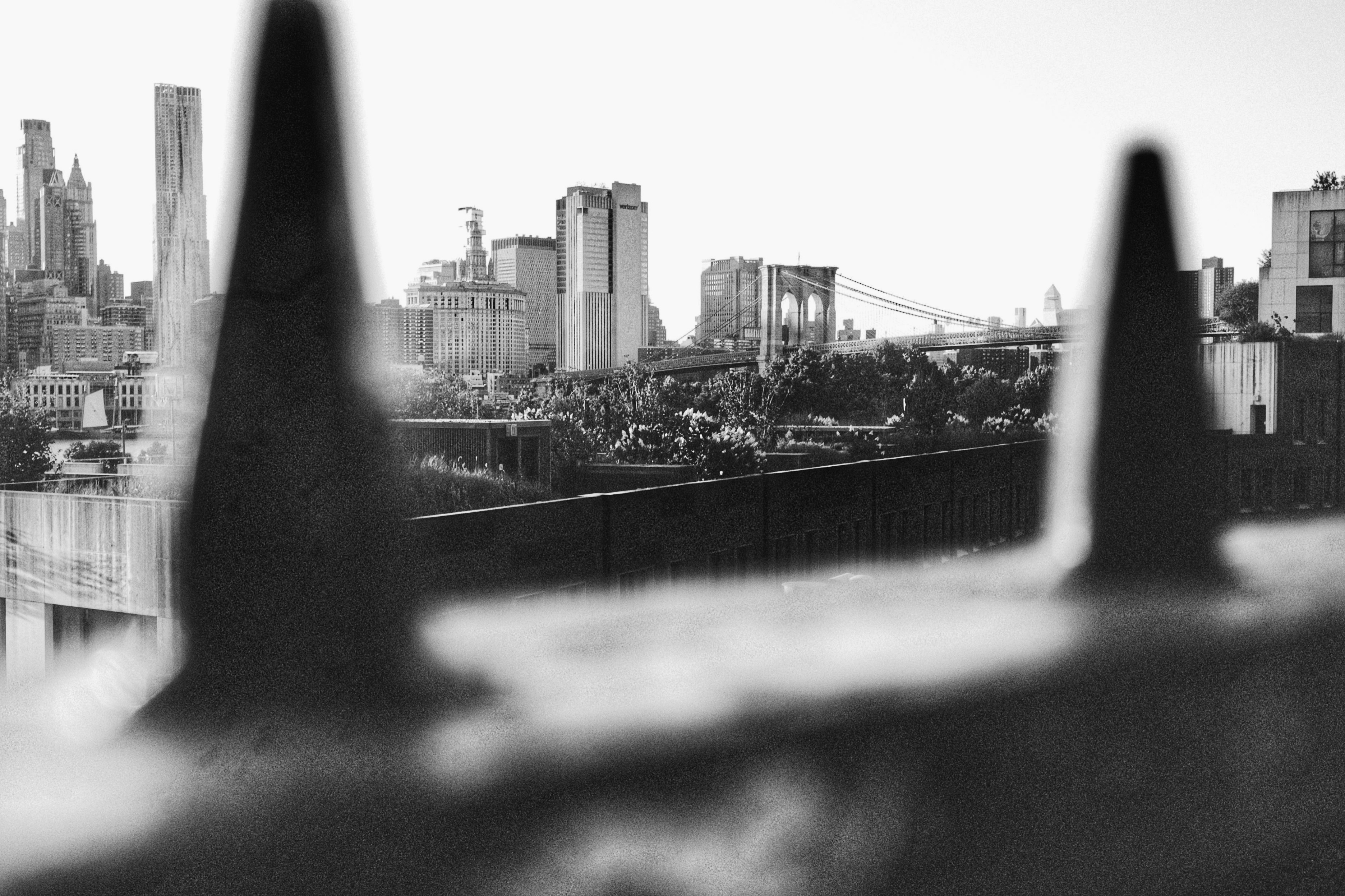 Black and white cityscape with bridge and fence.