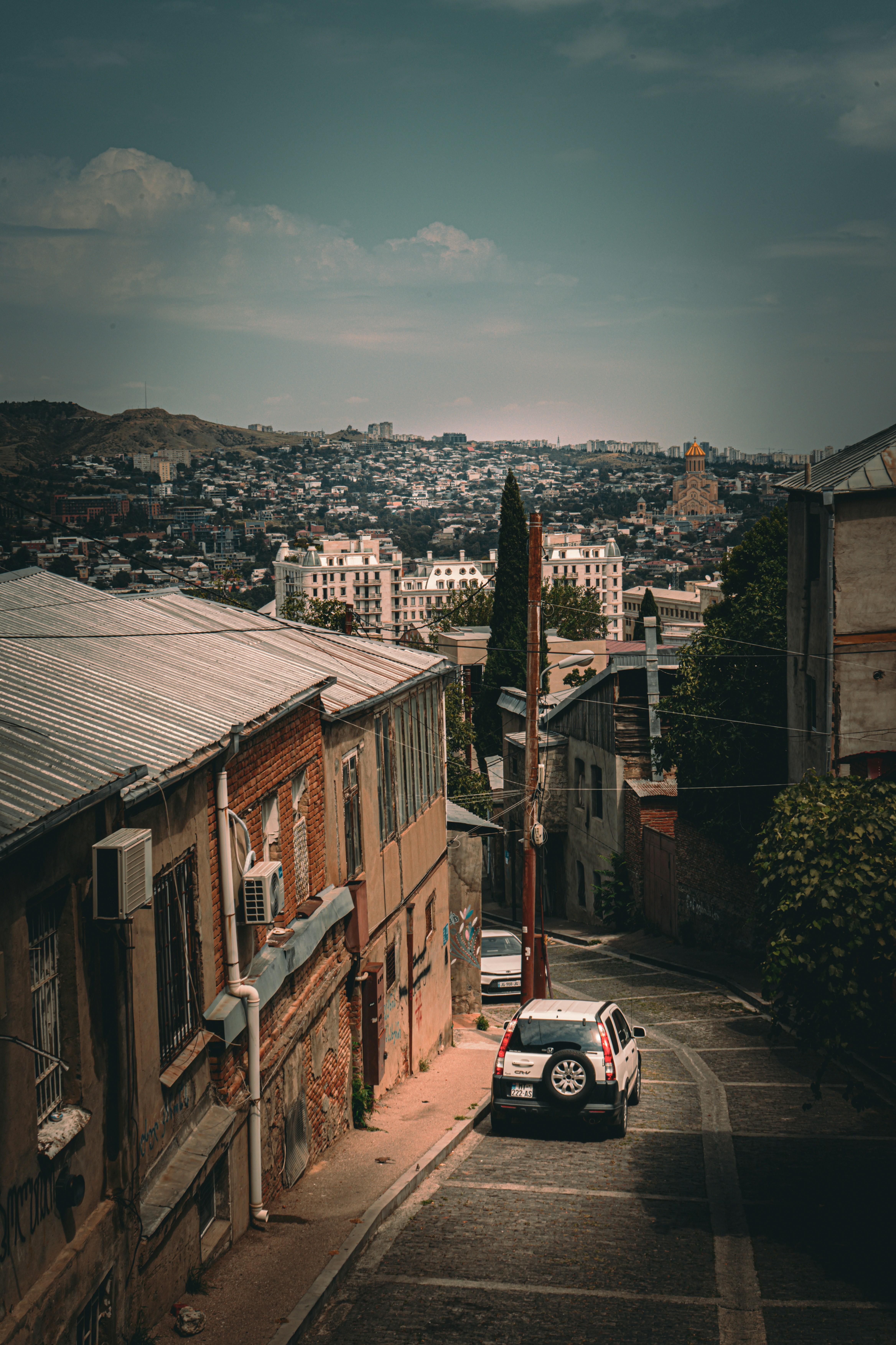Car driving down a narrow street in a city.