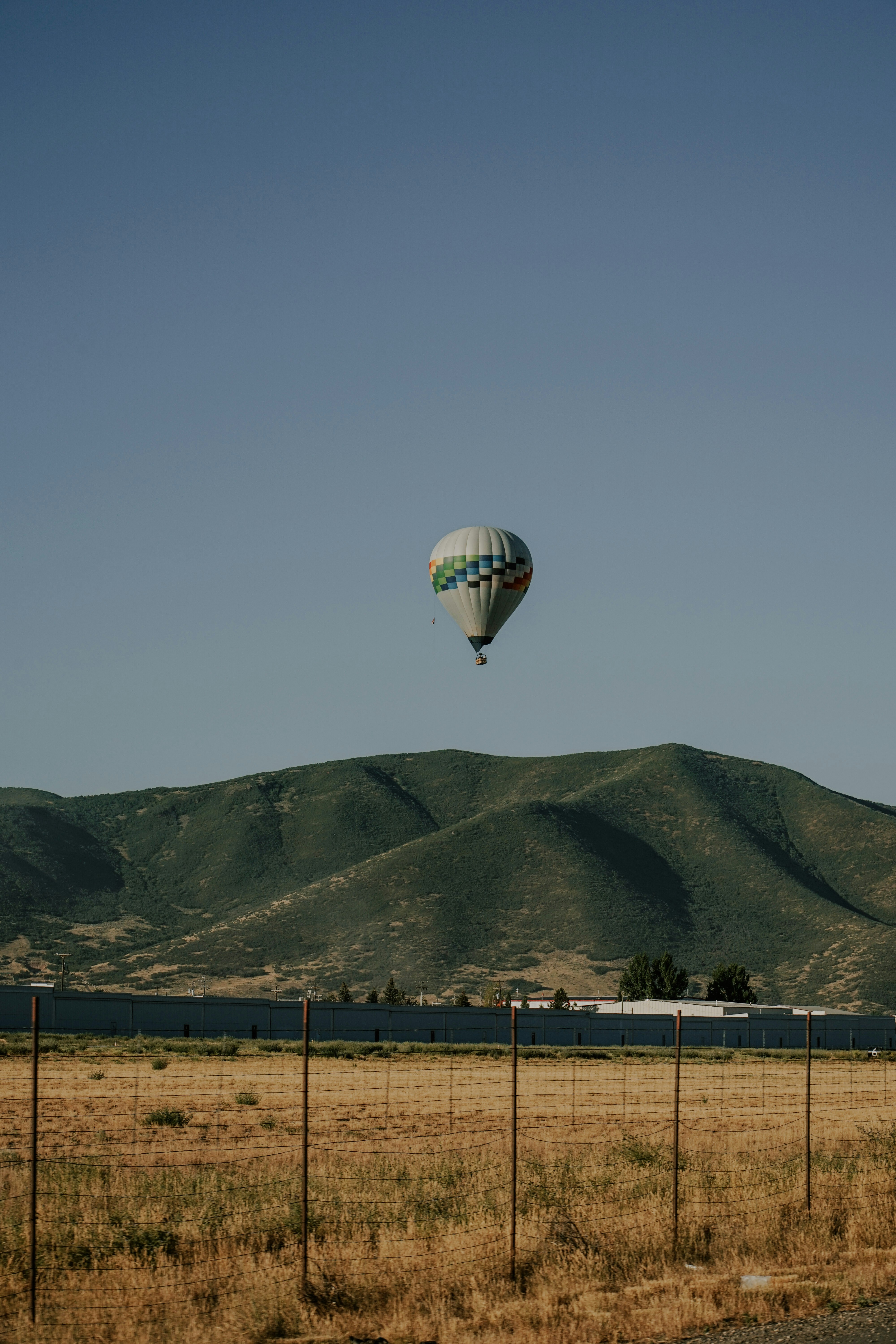 Hot air balloon floats over rolling hills