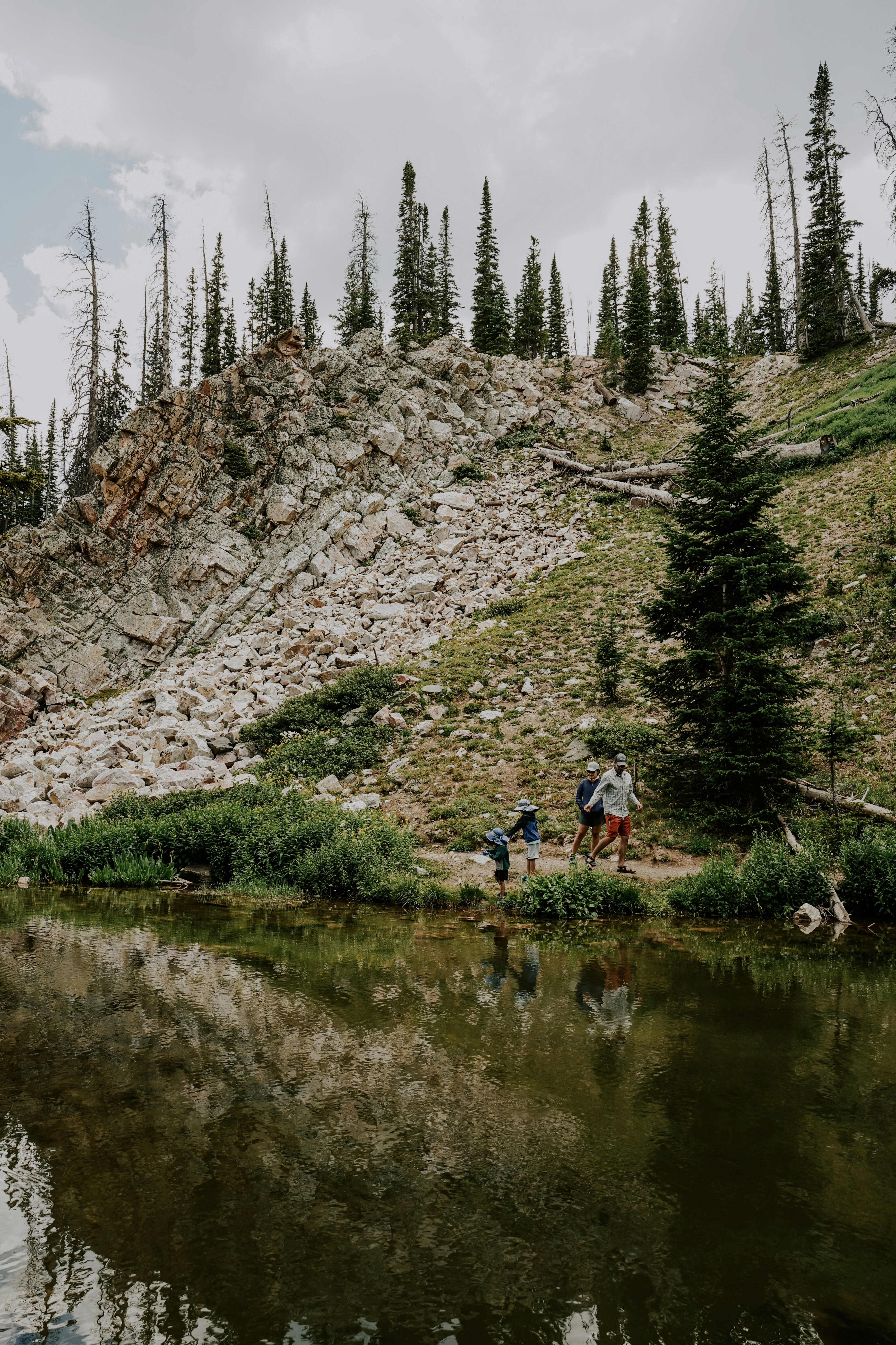 Hikers on a trail near a reflective mountain lake