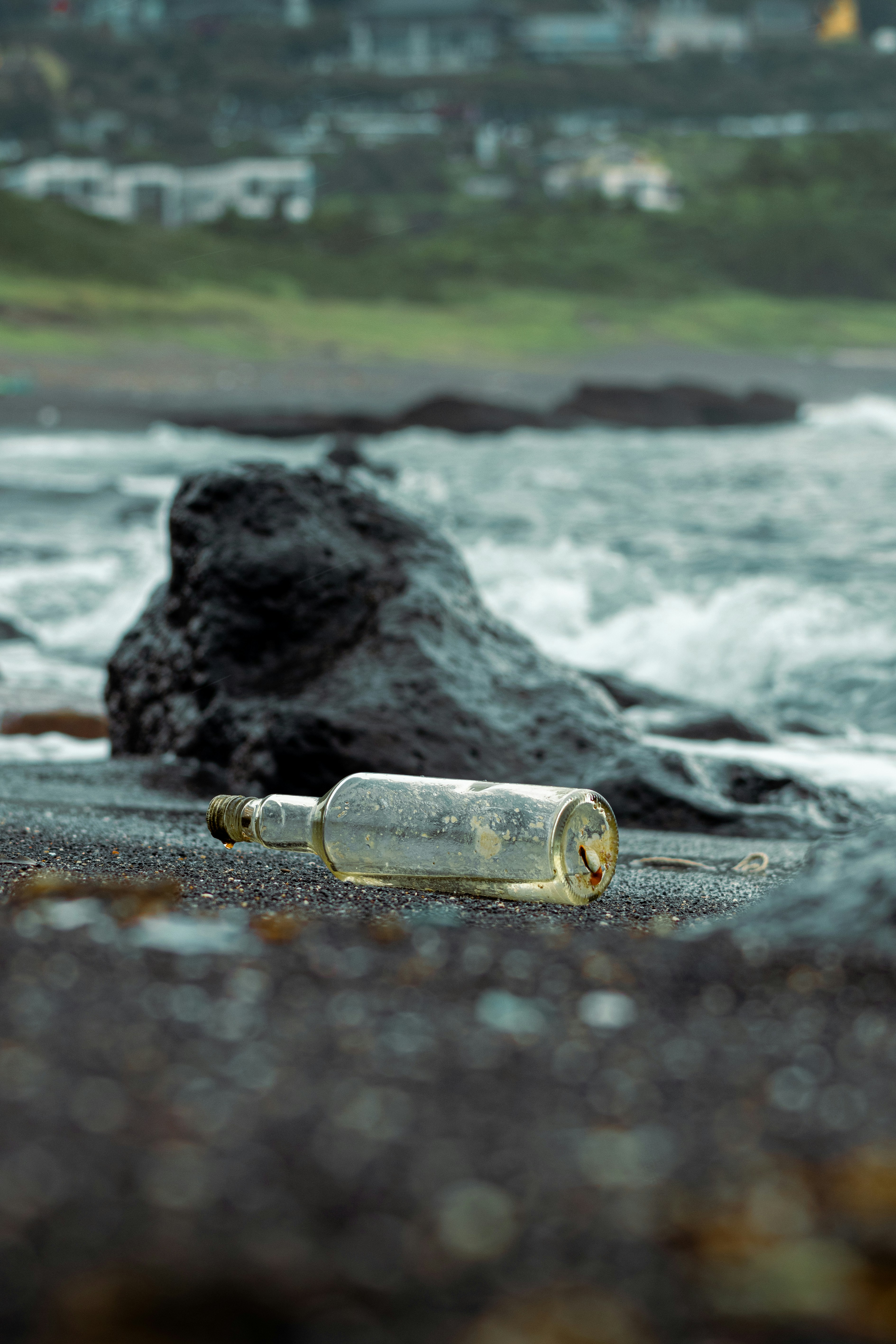 Lost in the Tide: A Glass Bottle Resting on a Rocky Shore