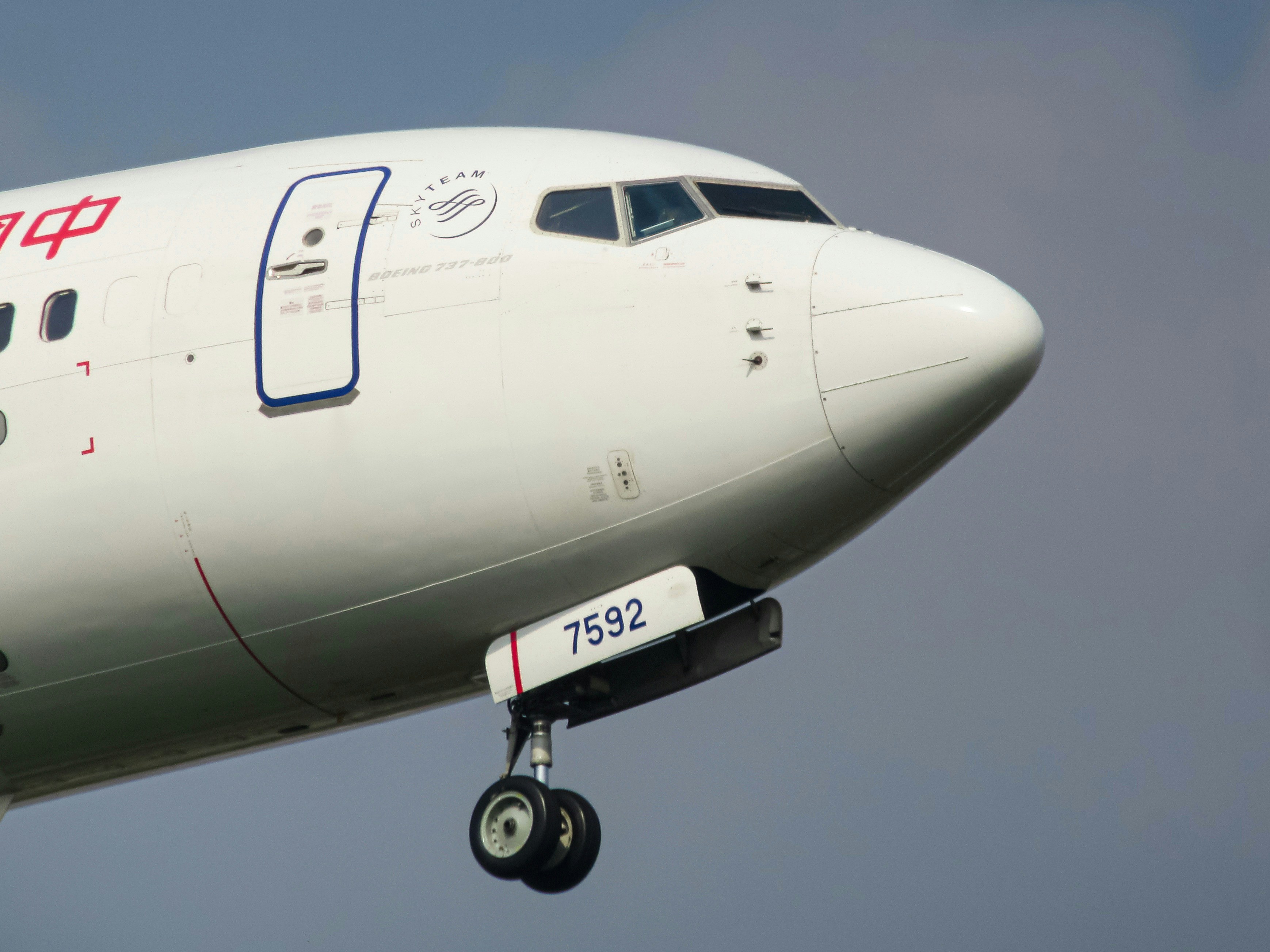 China Eastern Boeing 737-800 (B-7592) at VGHS | Close-up of a white airplane with landing gear down.