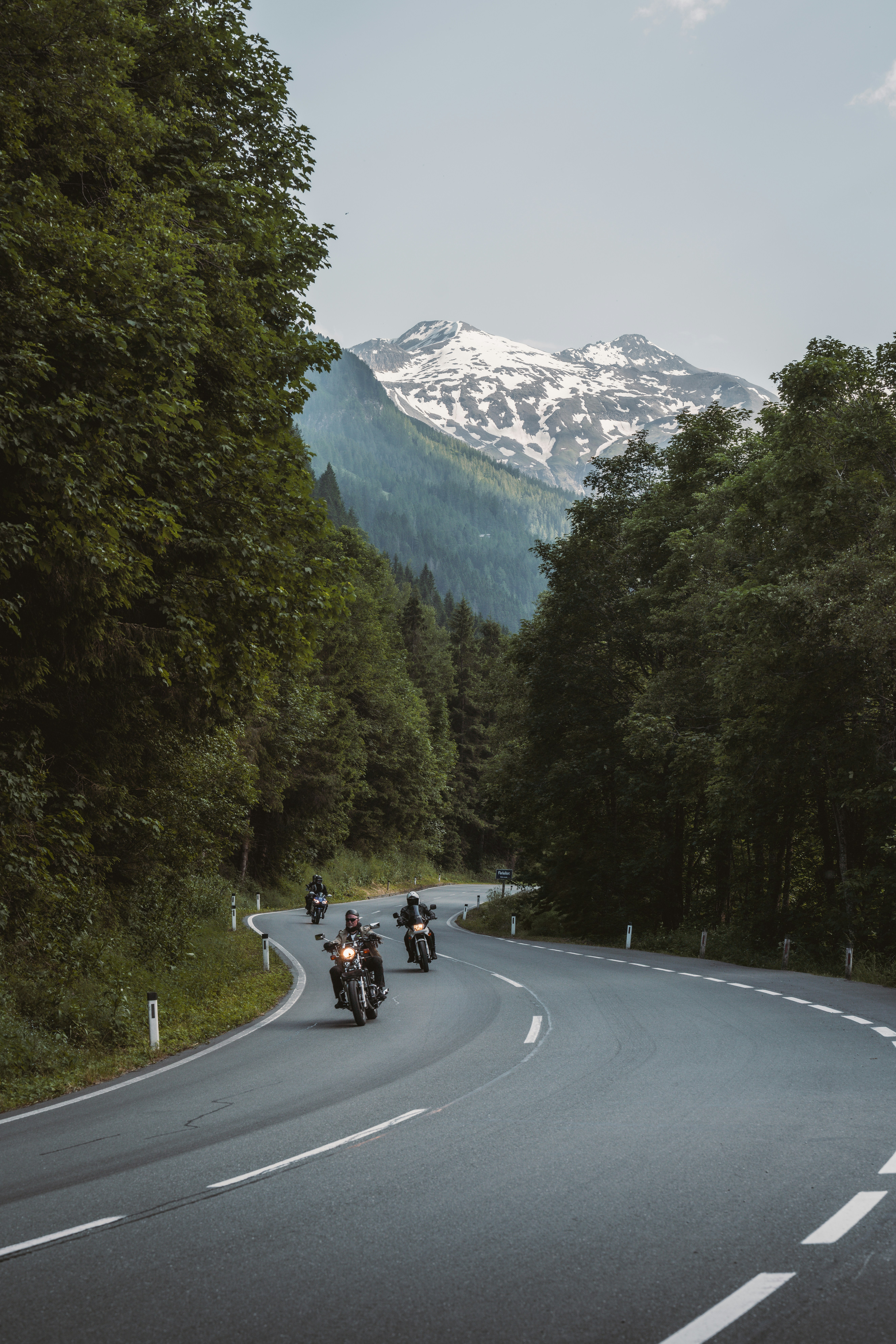 Bikers on Winding Alpine Road | Motorcyclists riding on a scenic mountain road