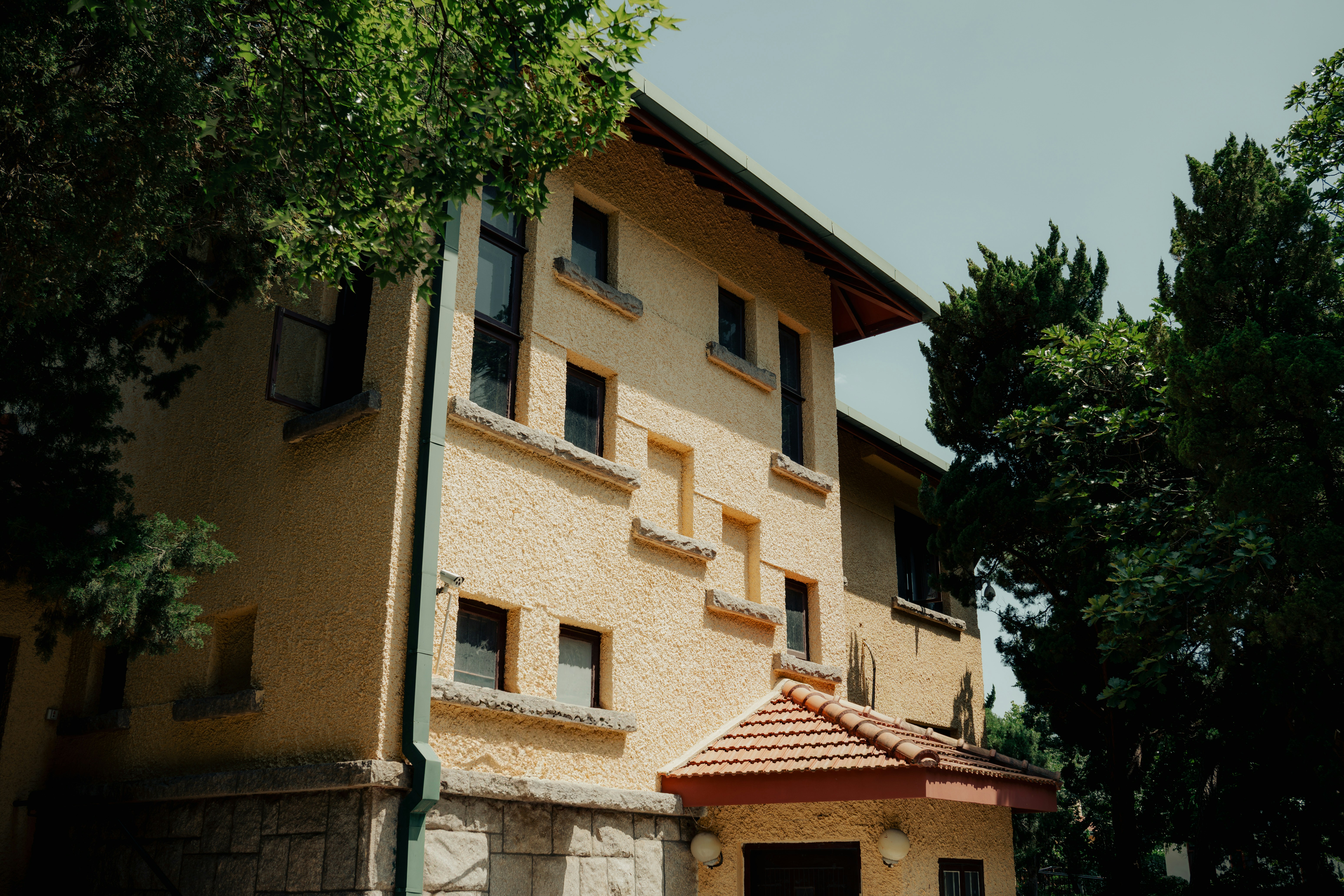 Mansion | A tan building with windows surrounded by green trees.