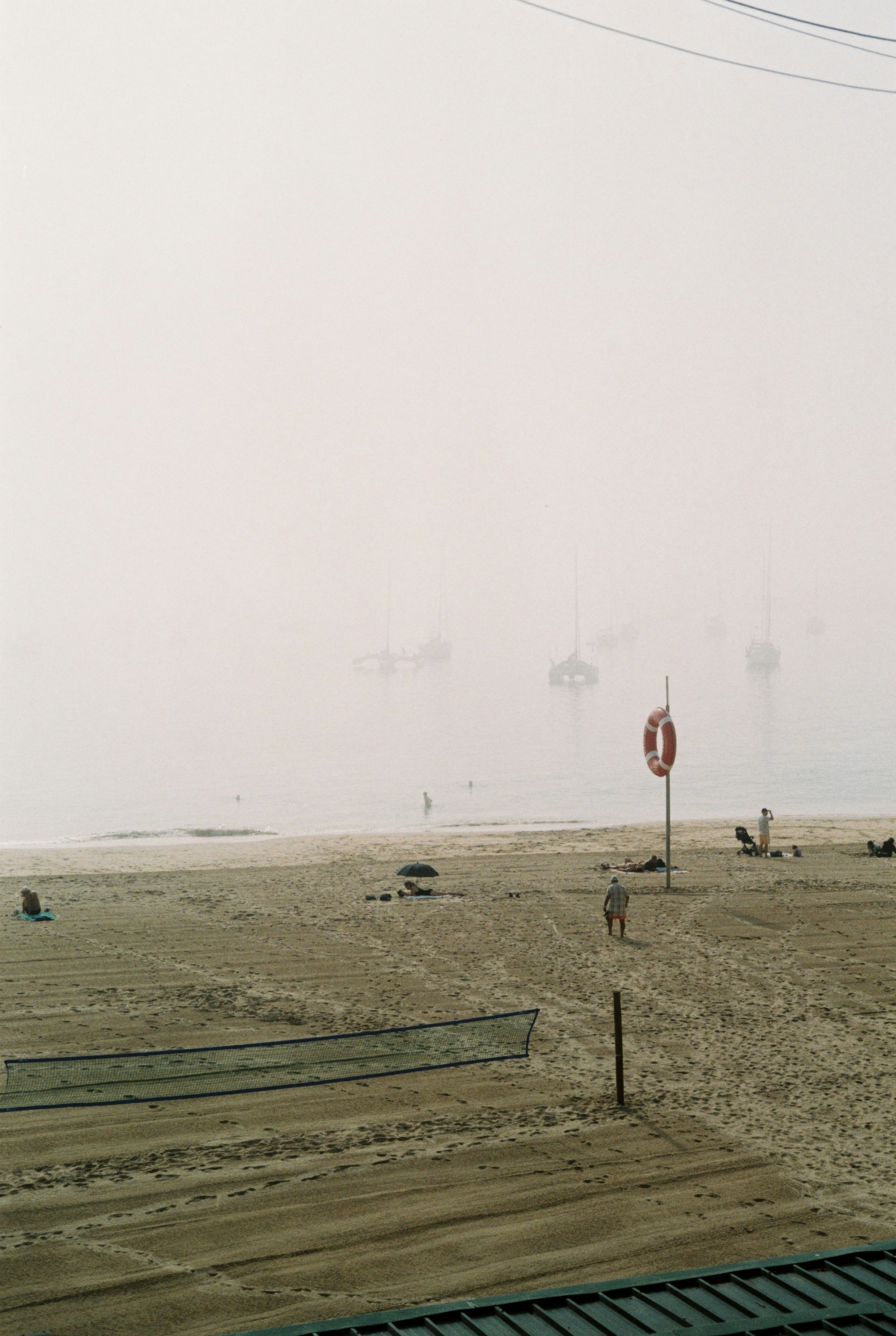 Foggy beach of Cascais | Misty beach with a signpost and distant structures