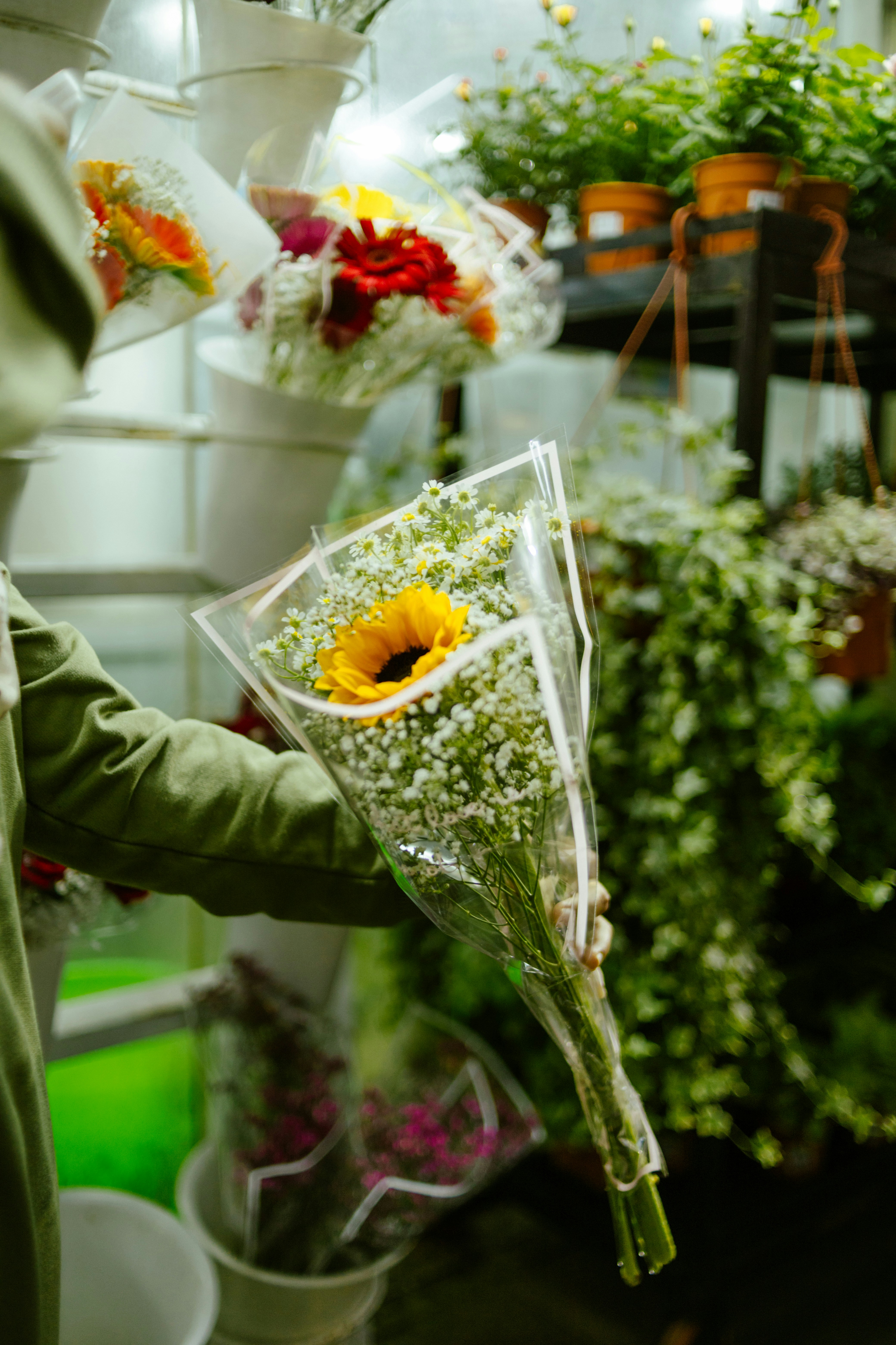 Person holding a bouquet of flowers with sunflower.