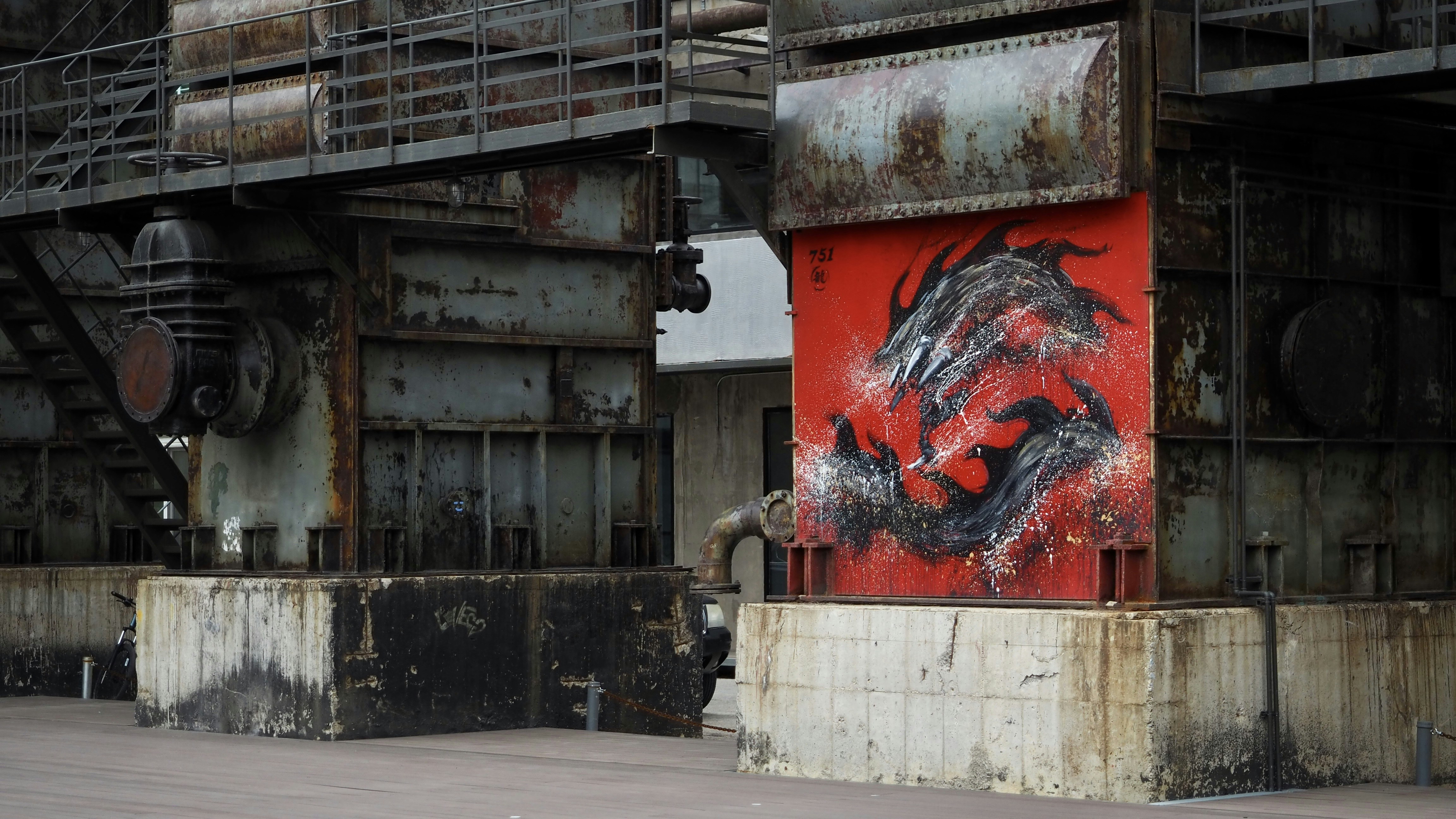 Red Dragon on Rust: A Steel Panel Amid Industrial Decay