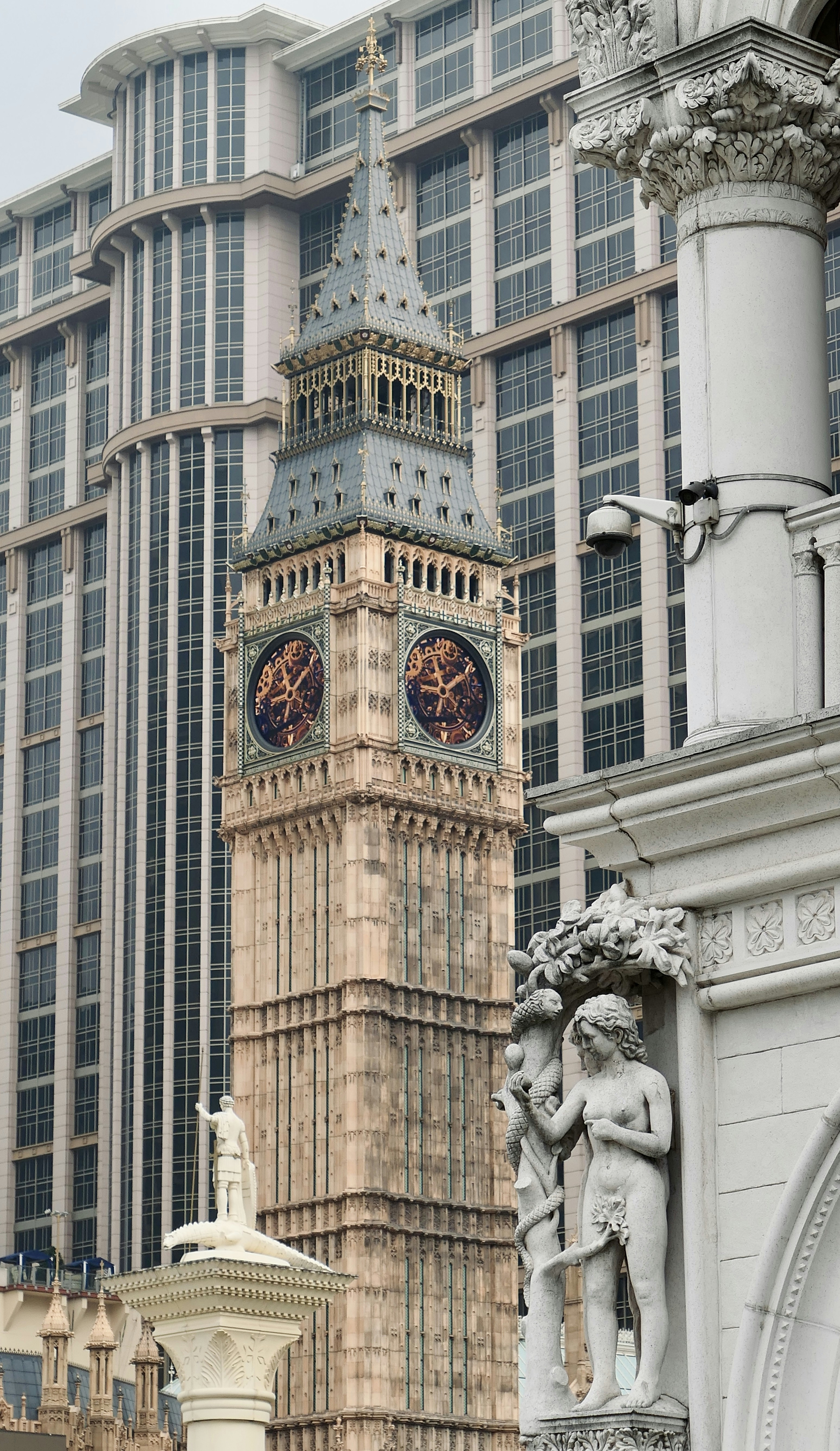 A detailed view of a clock tower with modern buildings behind it.