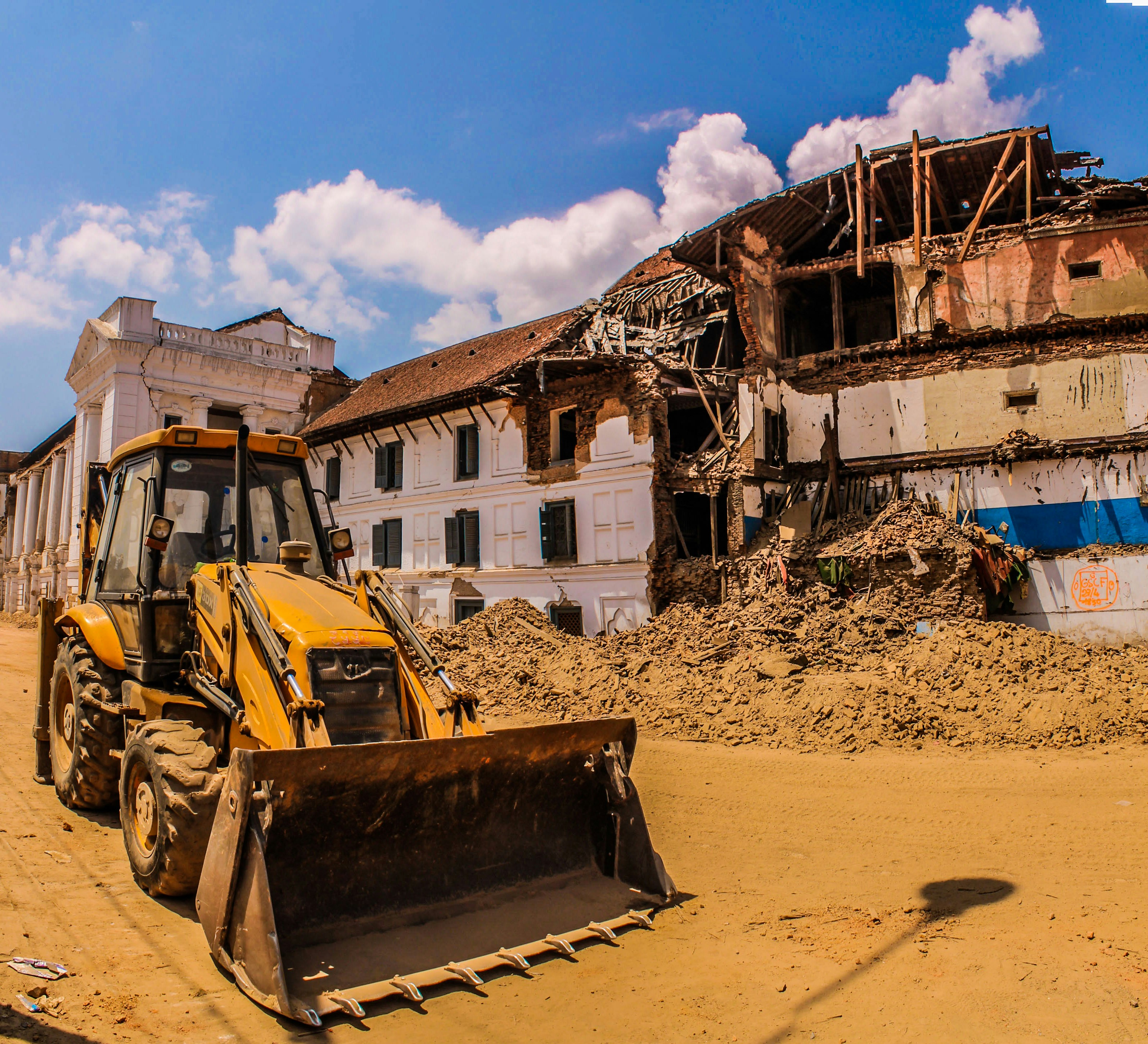 Bulldozer Clearing Rubble at Damaged Heritage Site | Bulldozer at a damaged building with debris