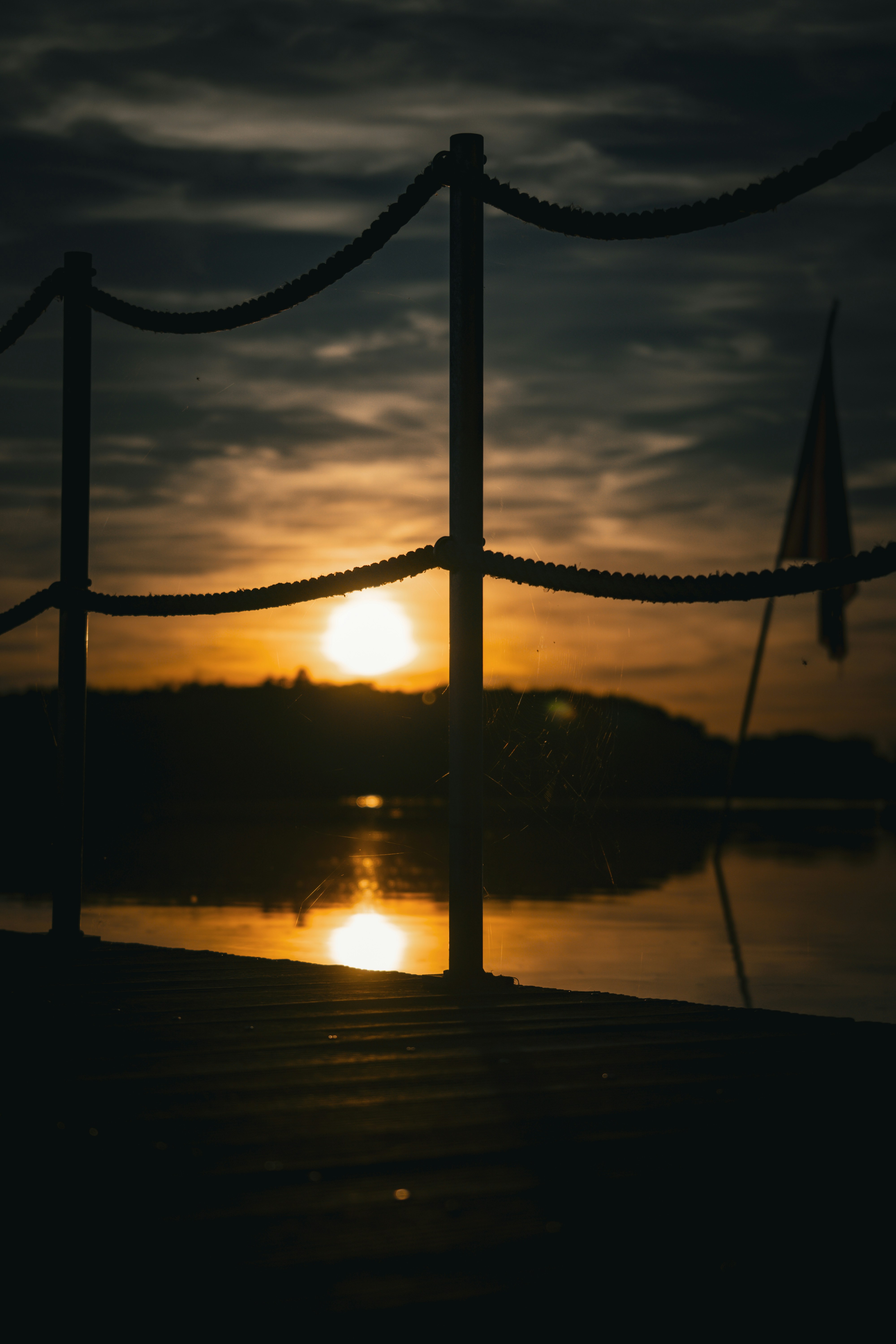 Sunset over calm water with railing in-focus railing