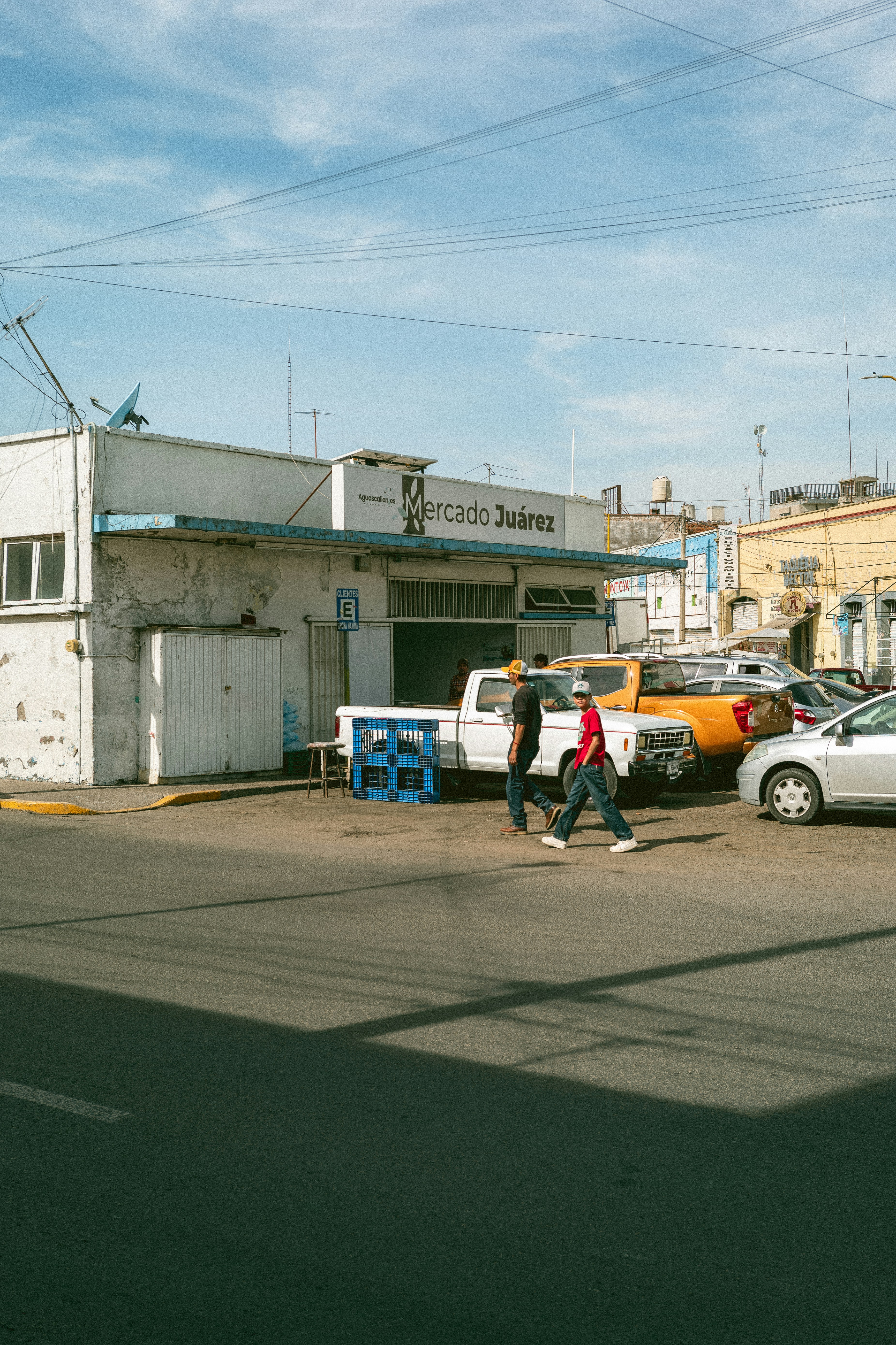 People standing outside a building with cars parked