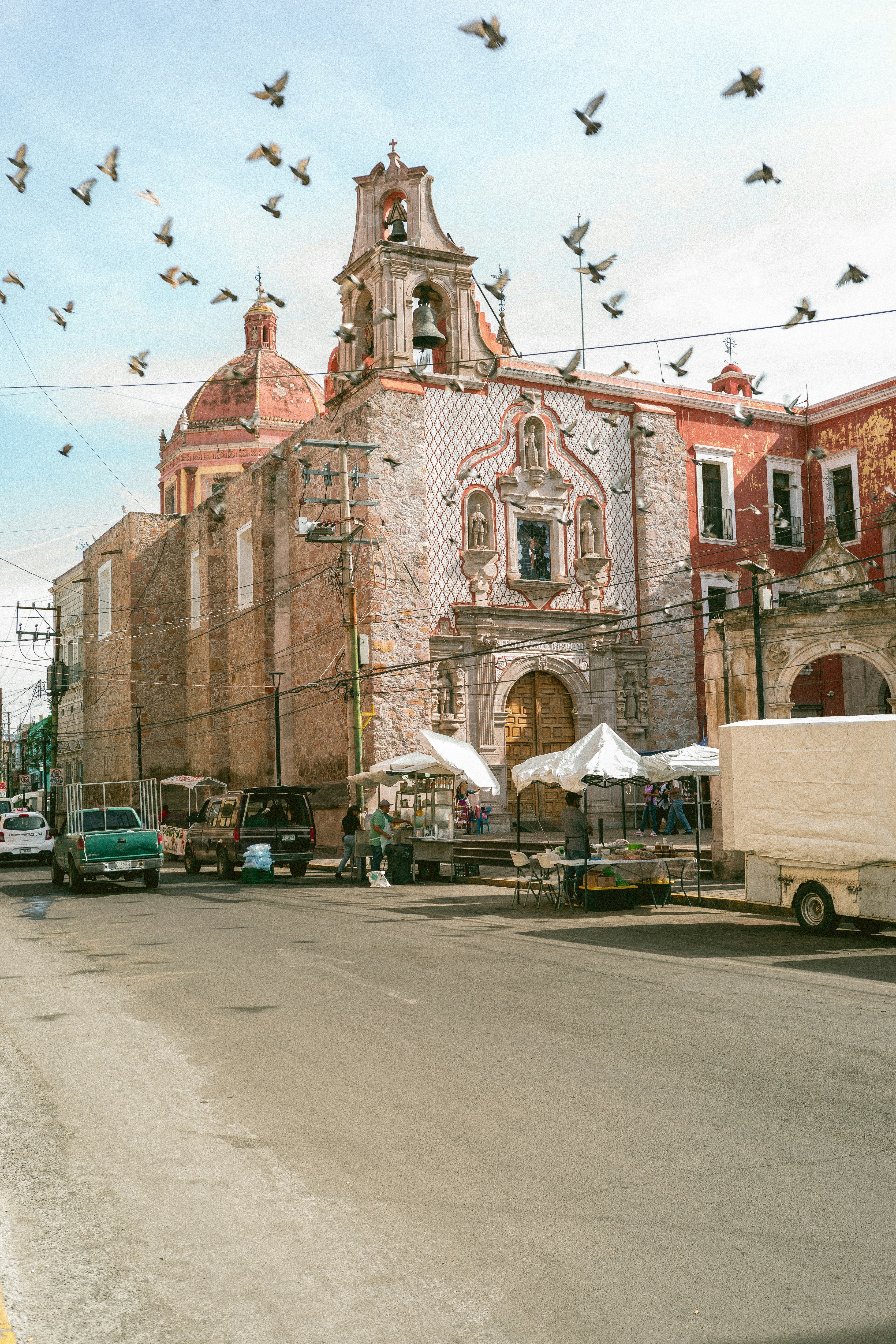 Pigeons fly over a historic church with ornate architecture.