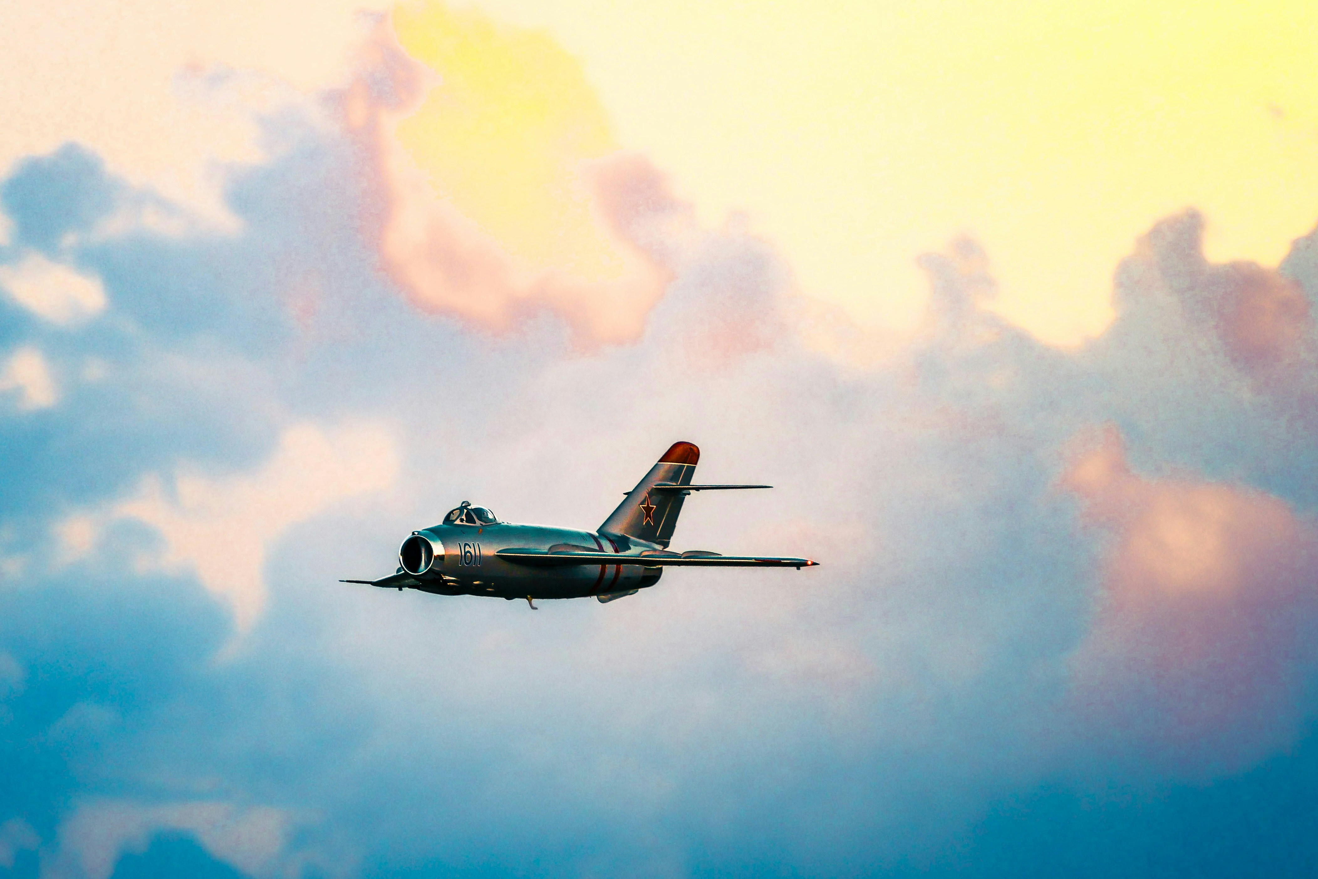 Jet airplane flying through clouds at sunset