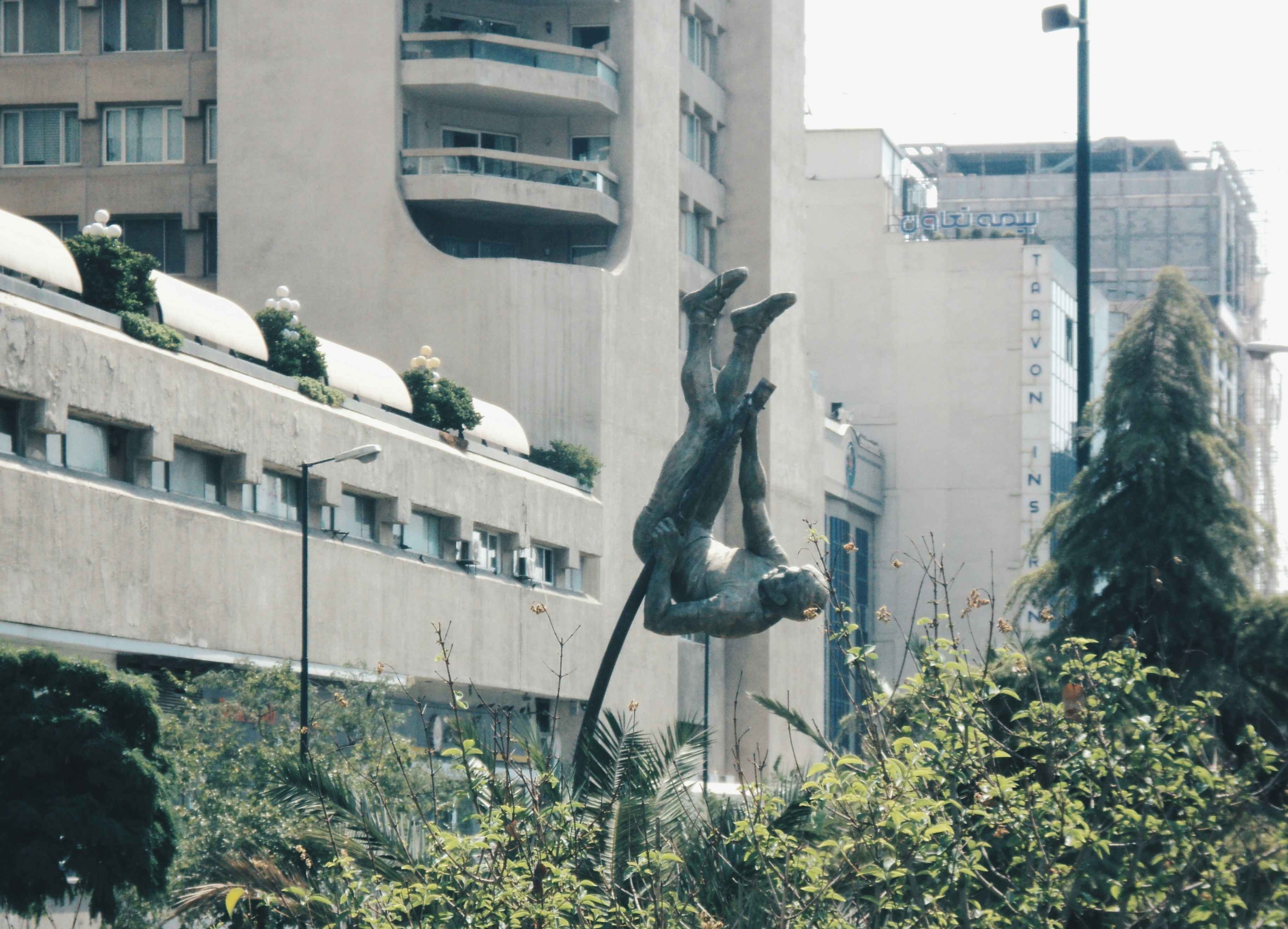 The city's own superhero. | Sculpture in front of modern buildings with trees