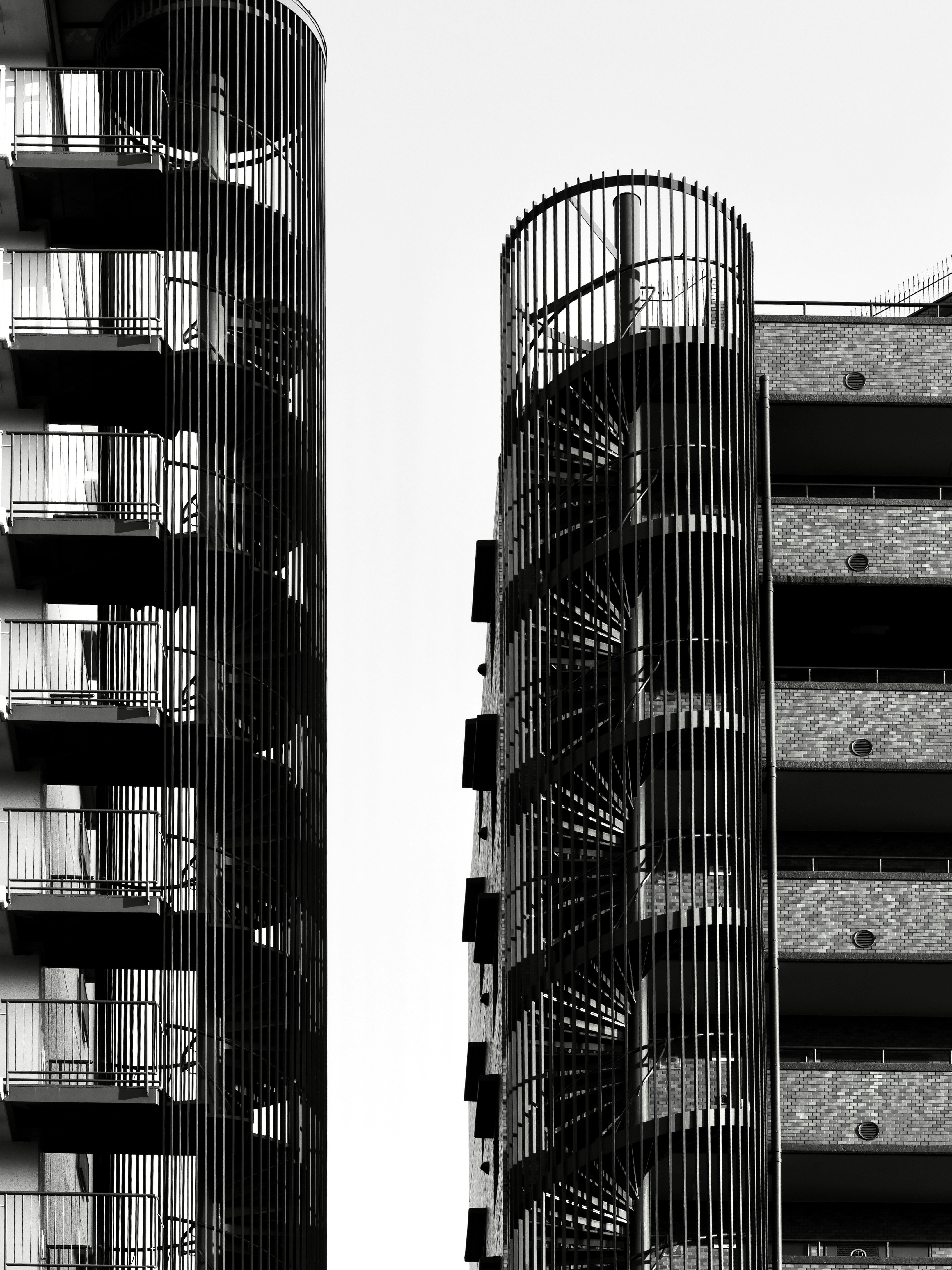 Two modern residential buildings with distinct architectural elements, showcasing intricate patterns and textures in black and white.