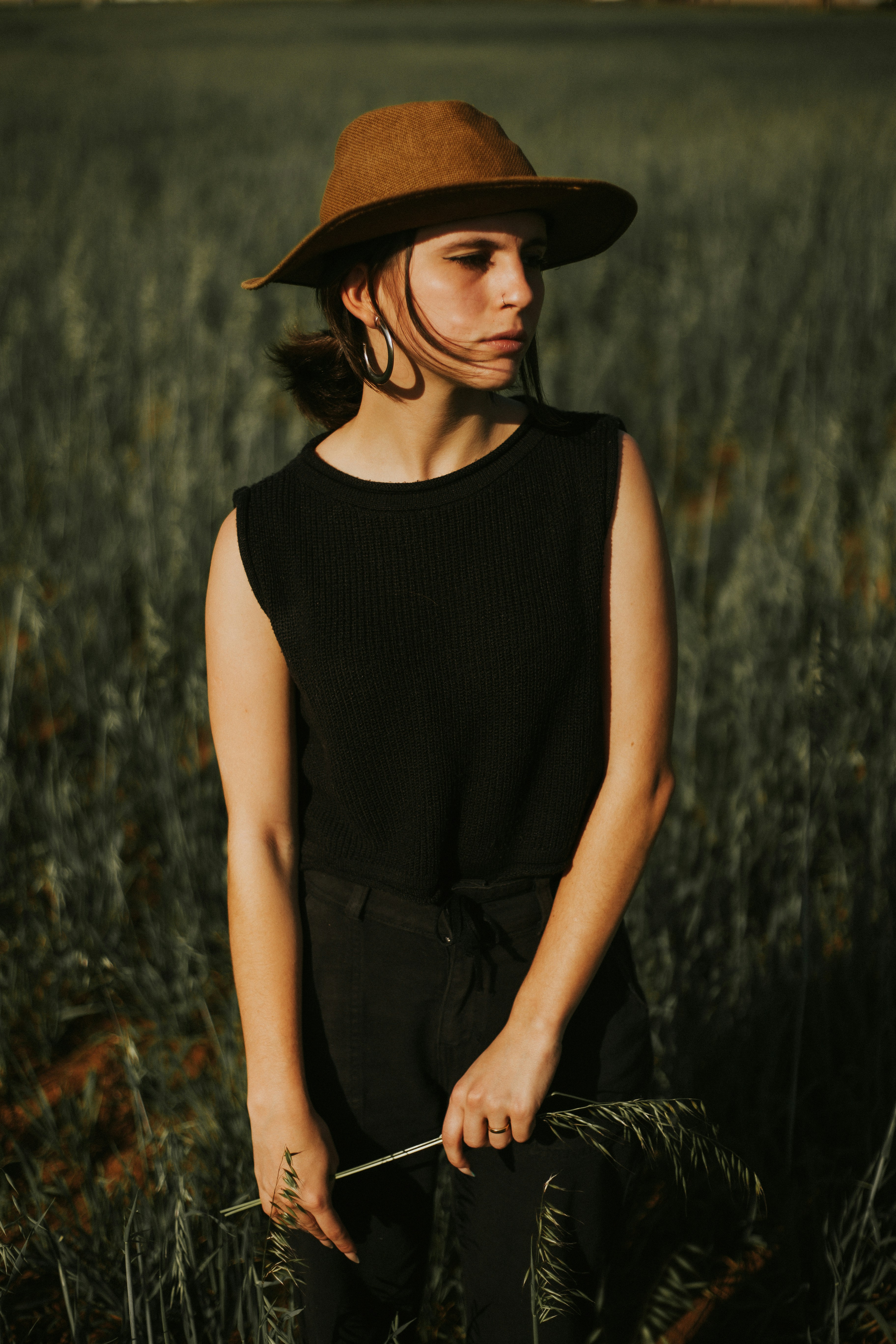 Woman in hat standing in field looking away