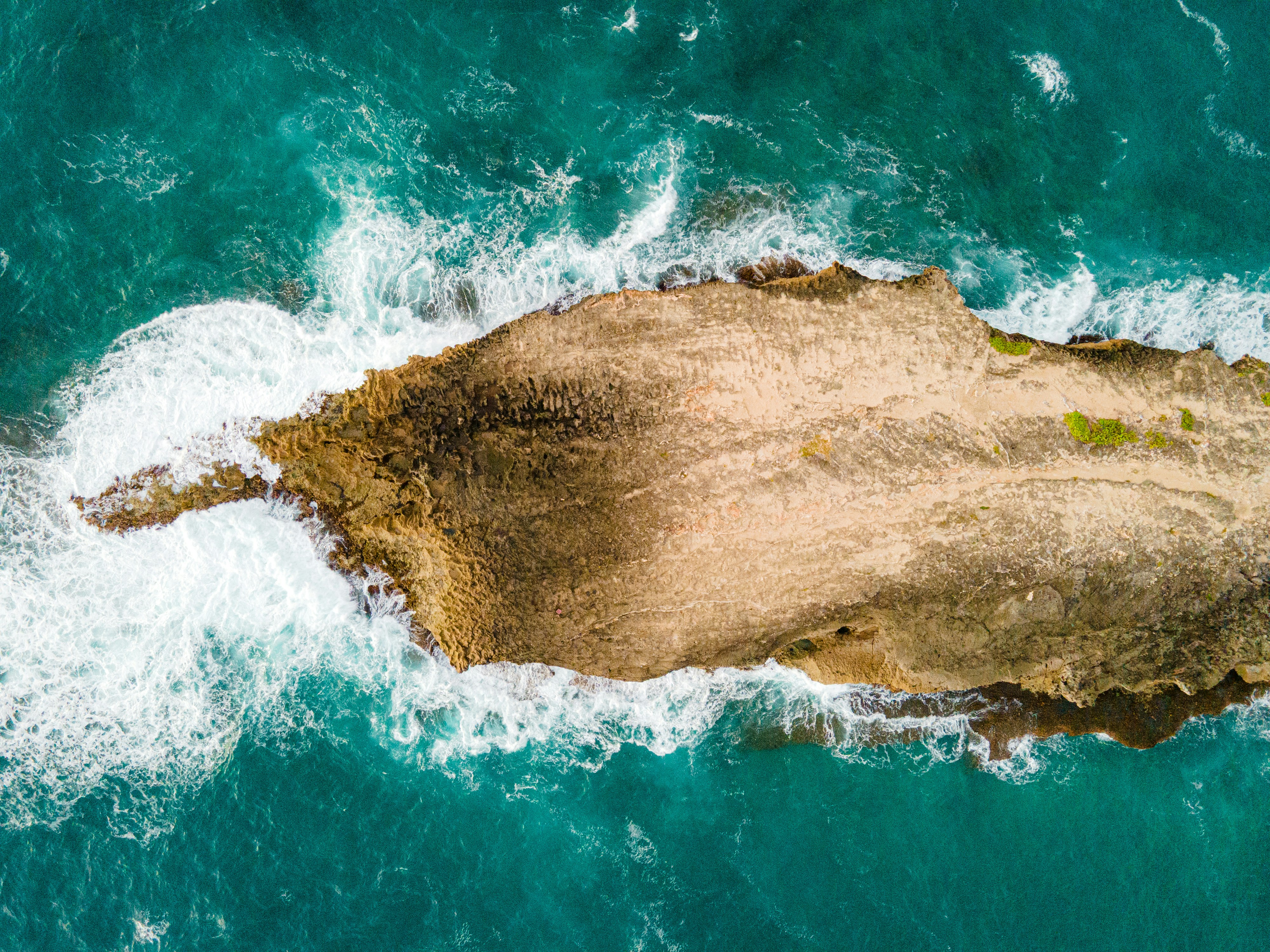 Waves crash against a rocky island formation.