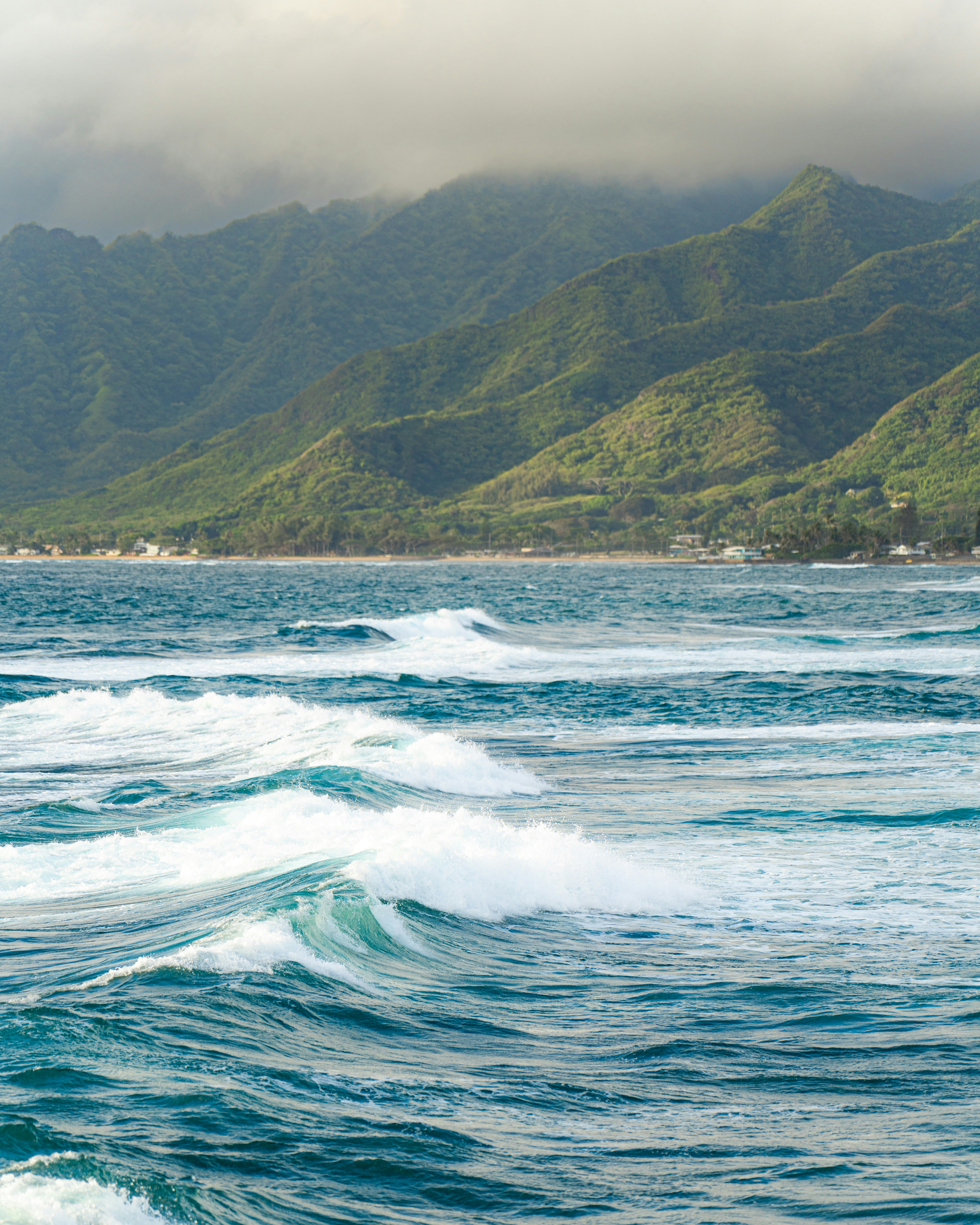Waves crash on the shore with misty mountains behind.