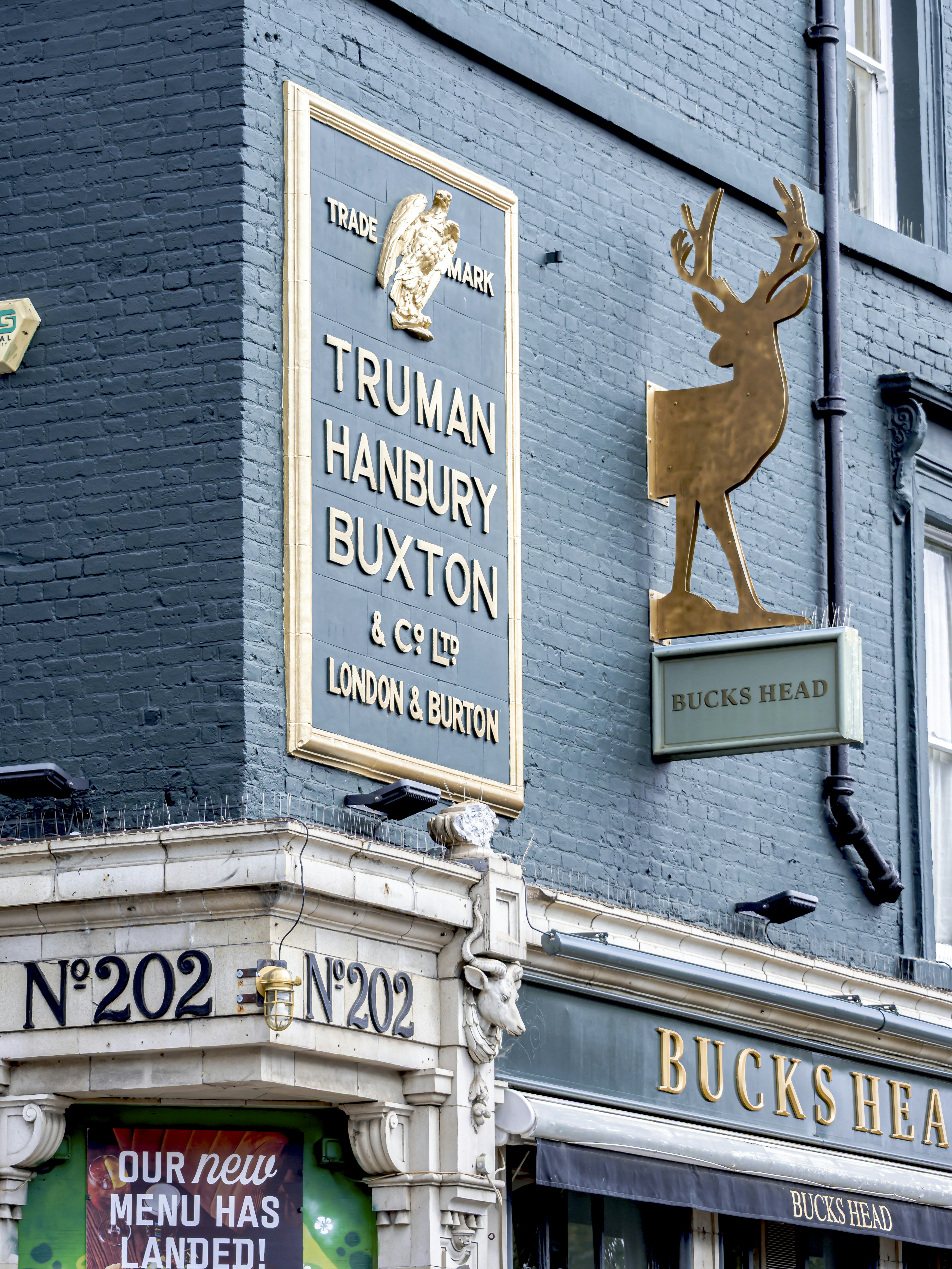 Heralded Town Sign: The Buck's Head of Buxton Under a Blue Brick Facade