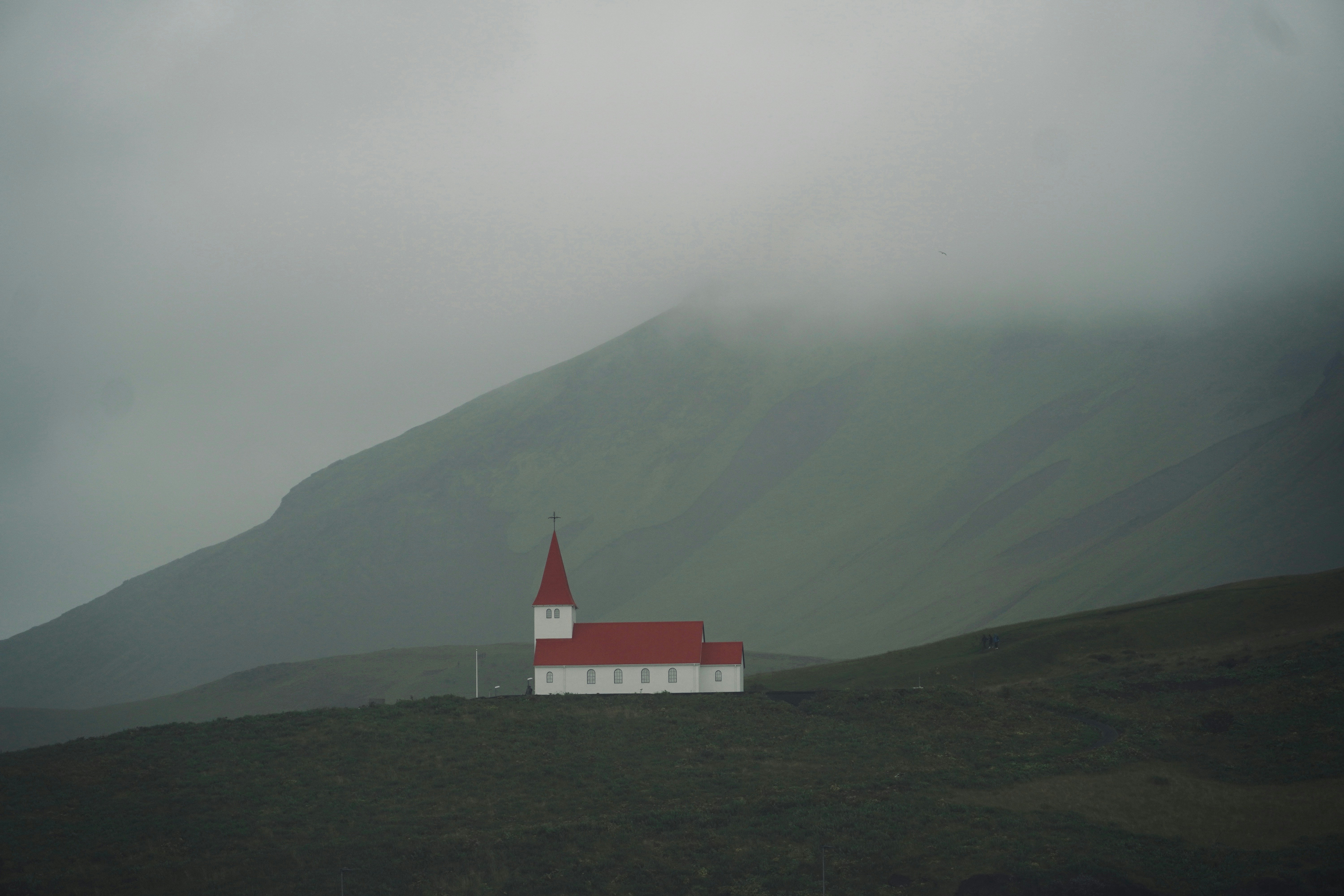 A small church stands on a misty hillside.