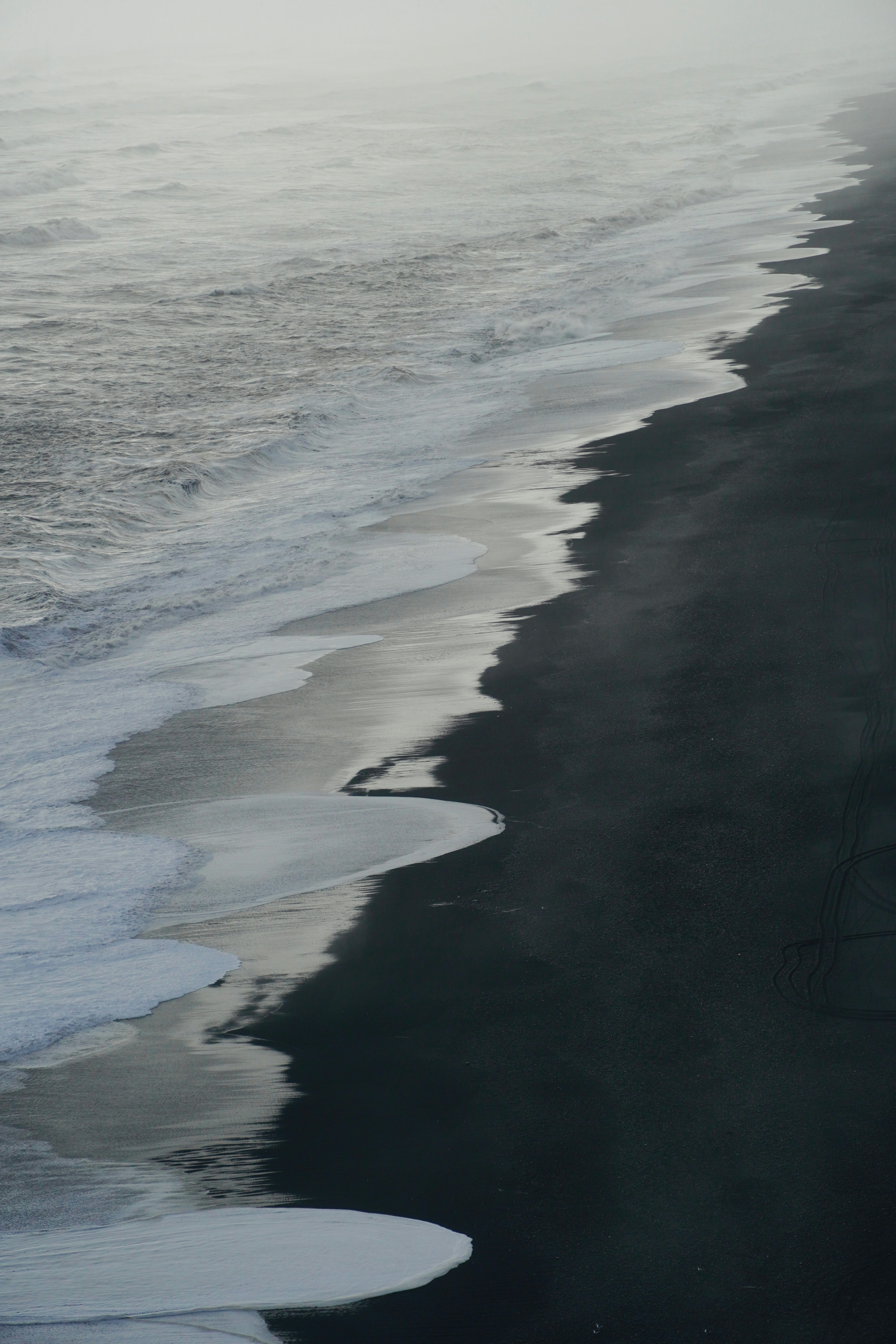 Waves washing over dark sand beach