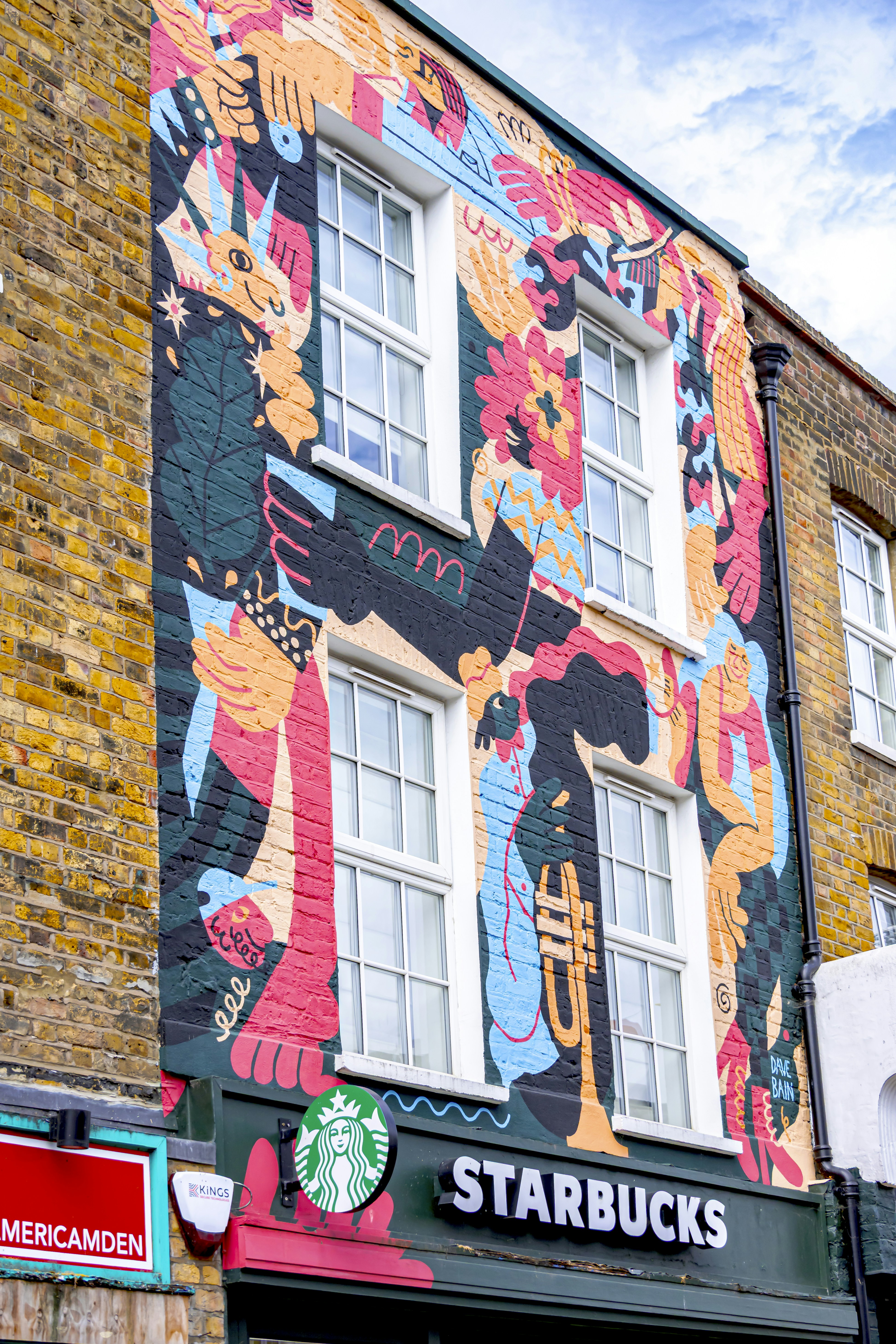 Colorful mural climbs the brick wall above a Starbucks storefront