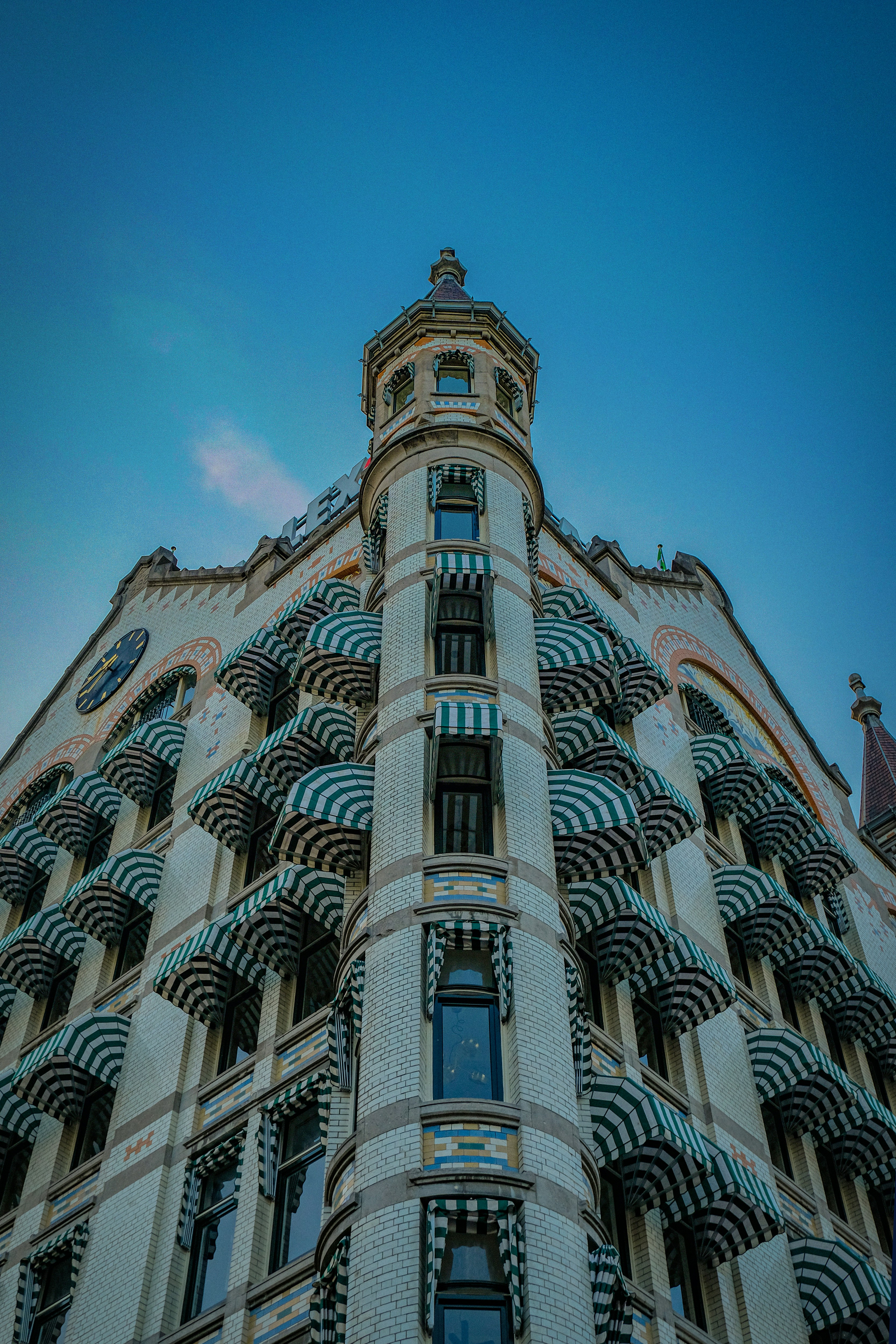 Summer night in Rotterdam, i casually walked by the Witte Huis, a place i've seen a 100 times, but i never actually paid attention to how pretty it actually is. It used to be the highest building in europe. For more information about this place: https://en.wikipedia.org/wiki/Witte_Huis | Historic building with ornate details against blue sky