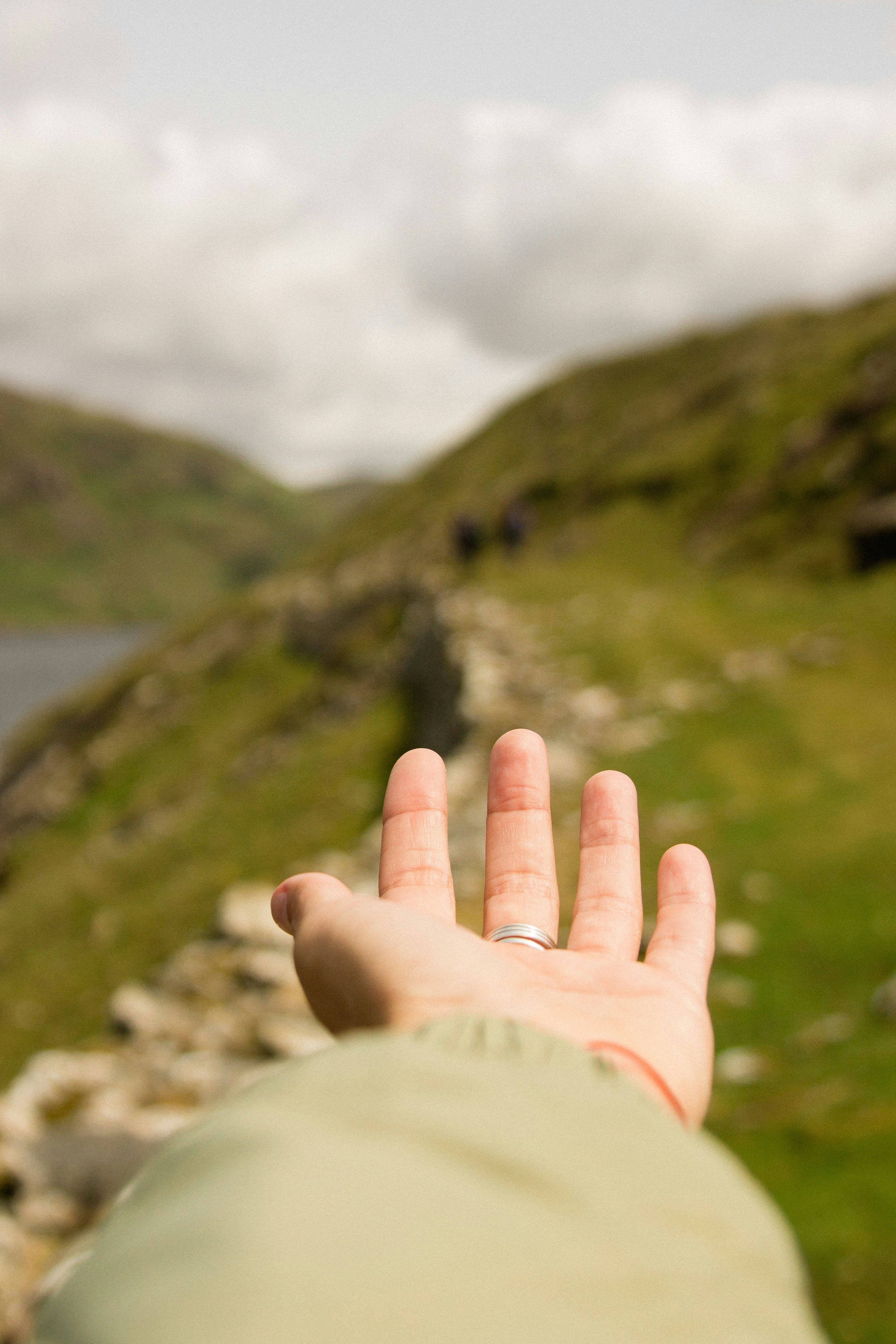 Hand Reaches Forward Over a Winding Ridge Path