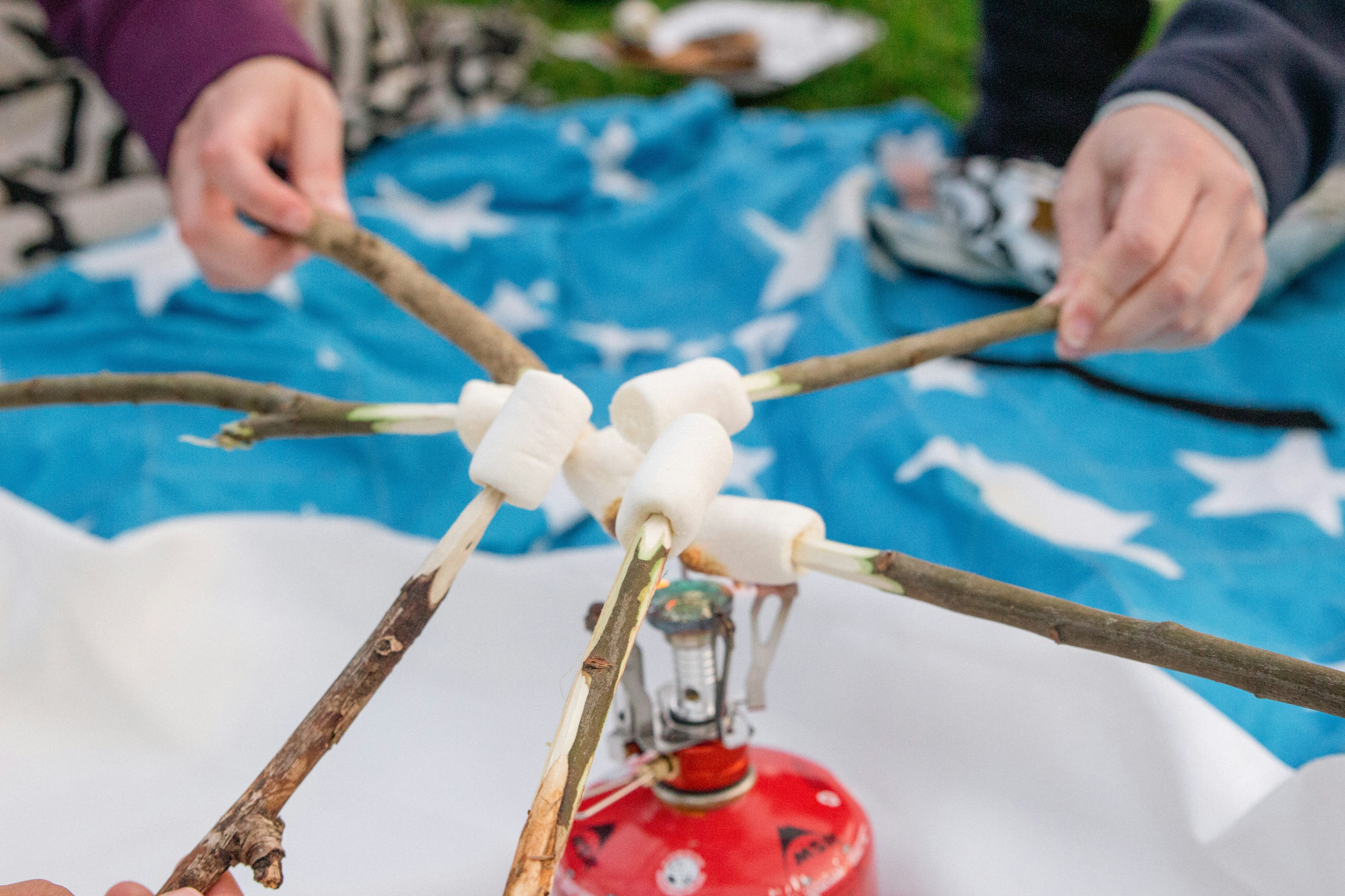 Hands roasting marshmallows over a small camping stove photo – Free ...
