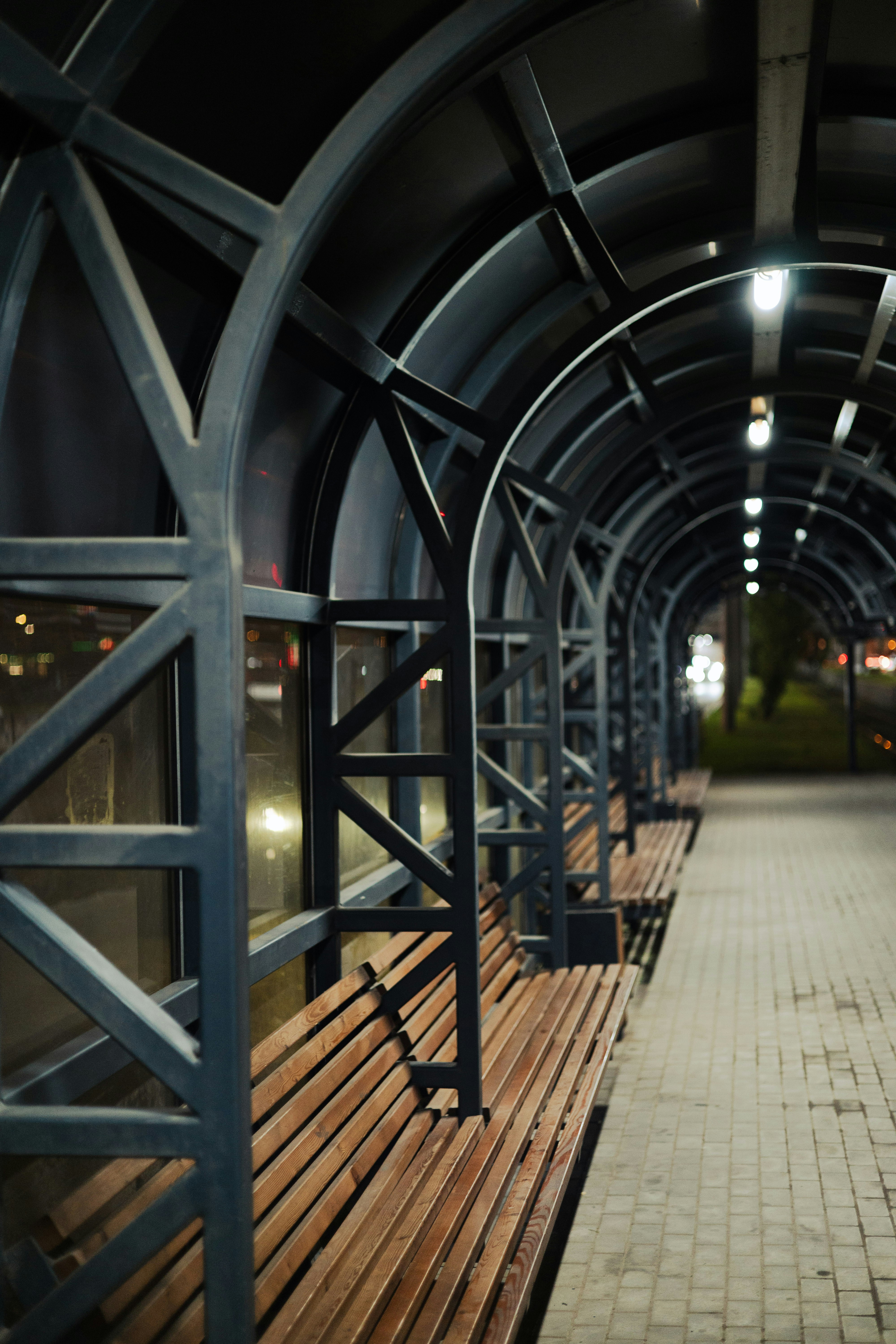 Modern bus shelter interior featuring geometric metal structures and illuminated benches, creating a blend of comfort and design.